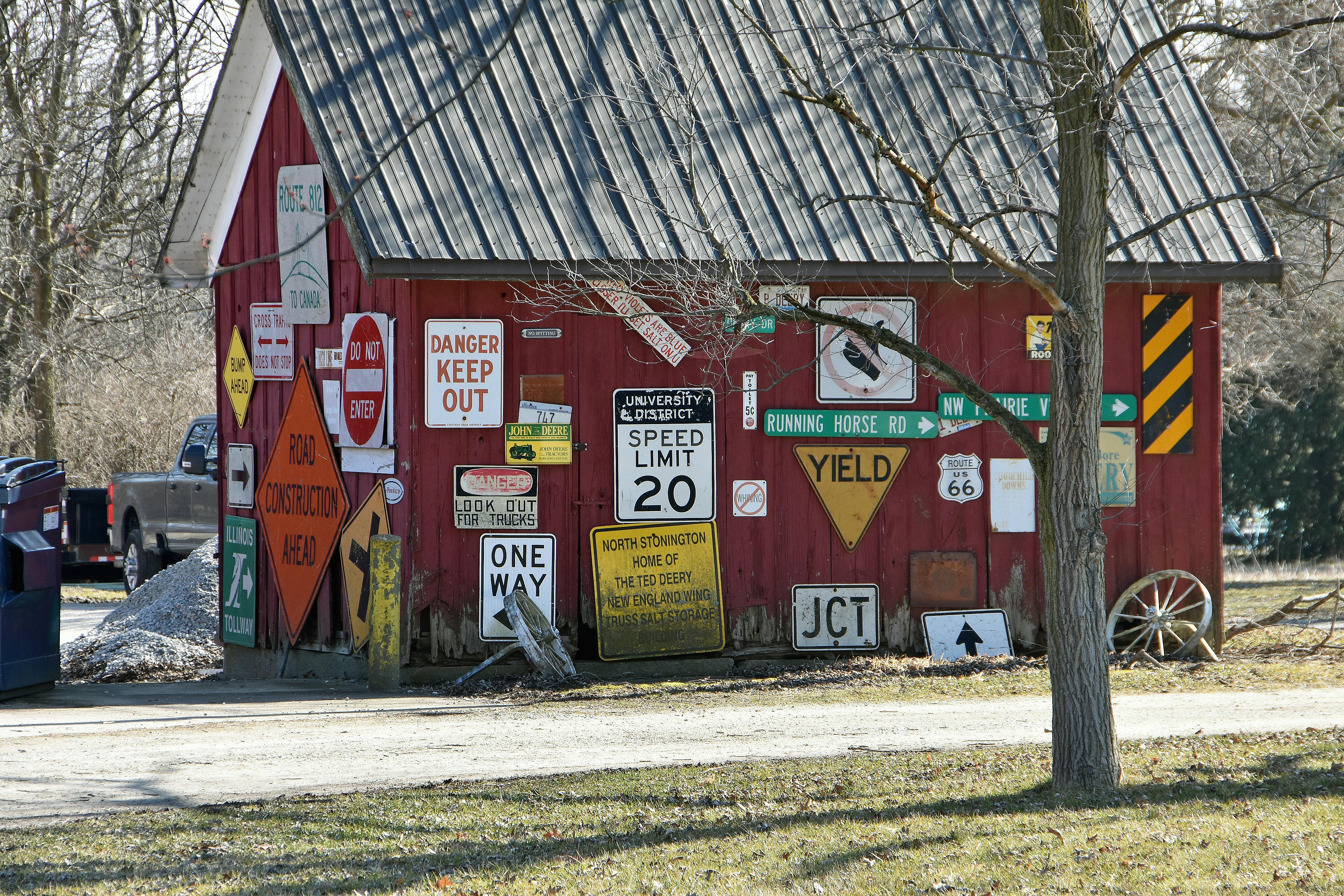 Rustic Shed Adorned with Vintage Road Signs · Free Stock Photo