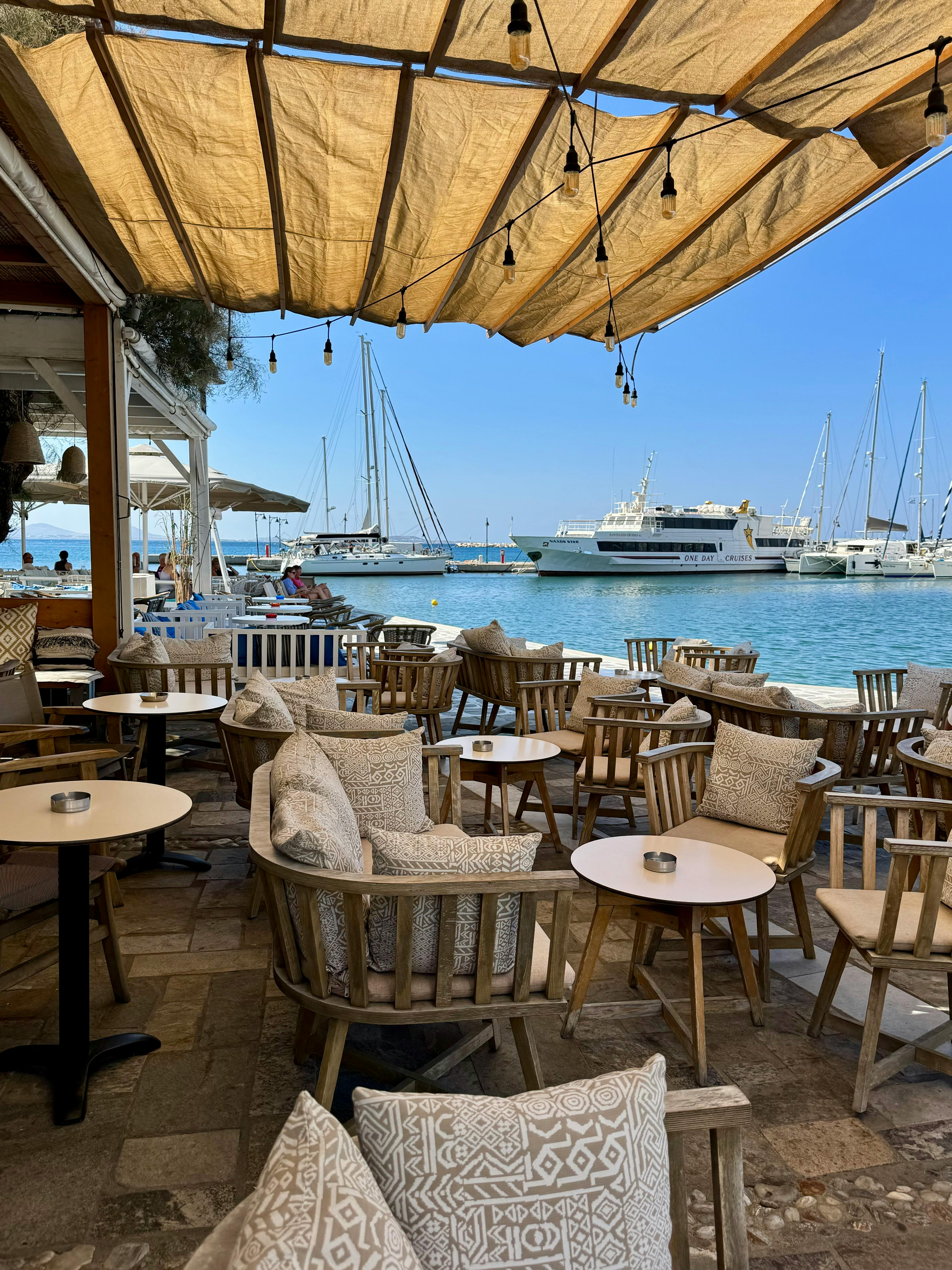 Coastal Outdoor Café with Sailboats · Free Stock Photo
