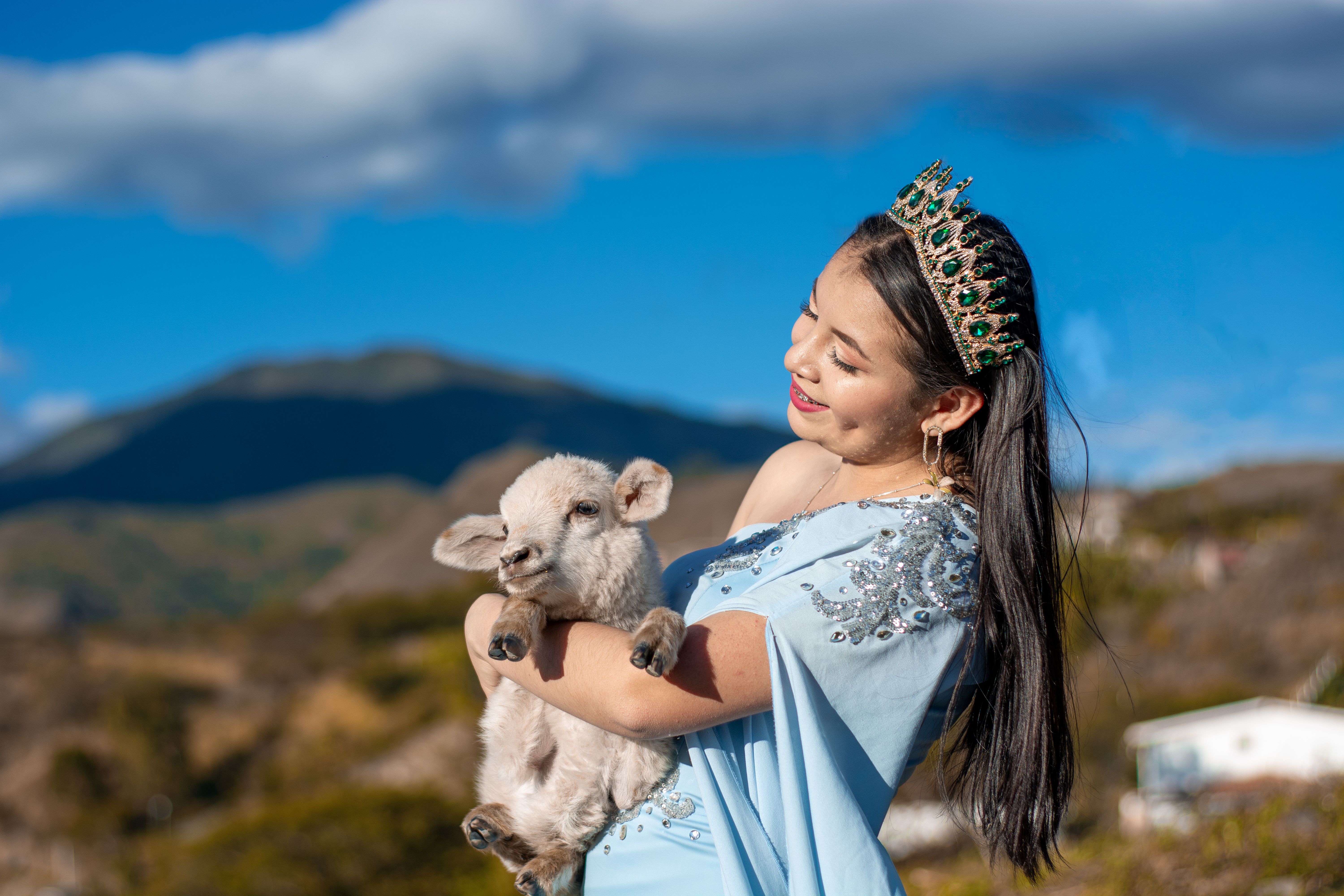 Majestic Woman Holding Lamb in Scenic Mountain View · Free Stock Photo