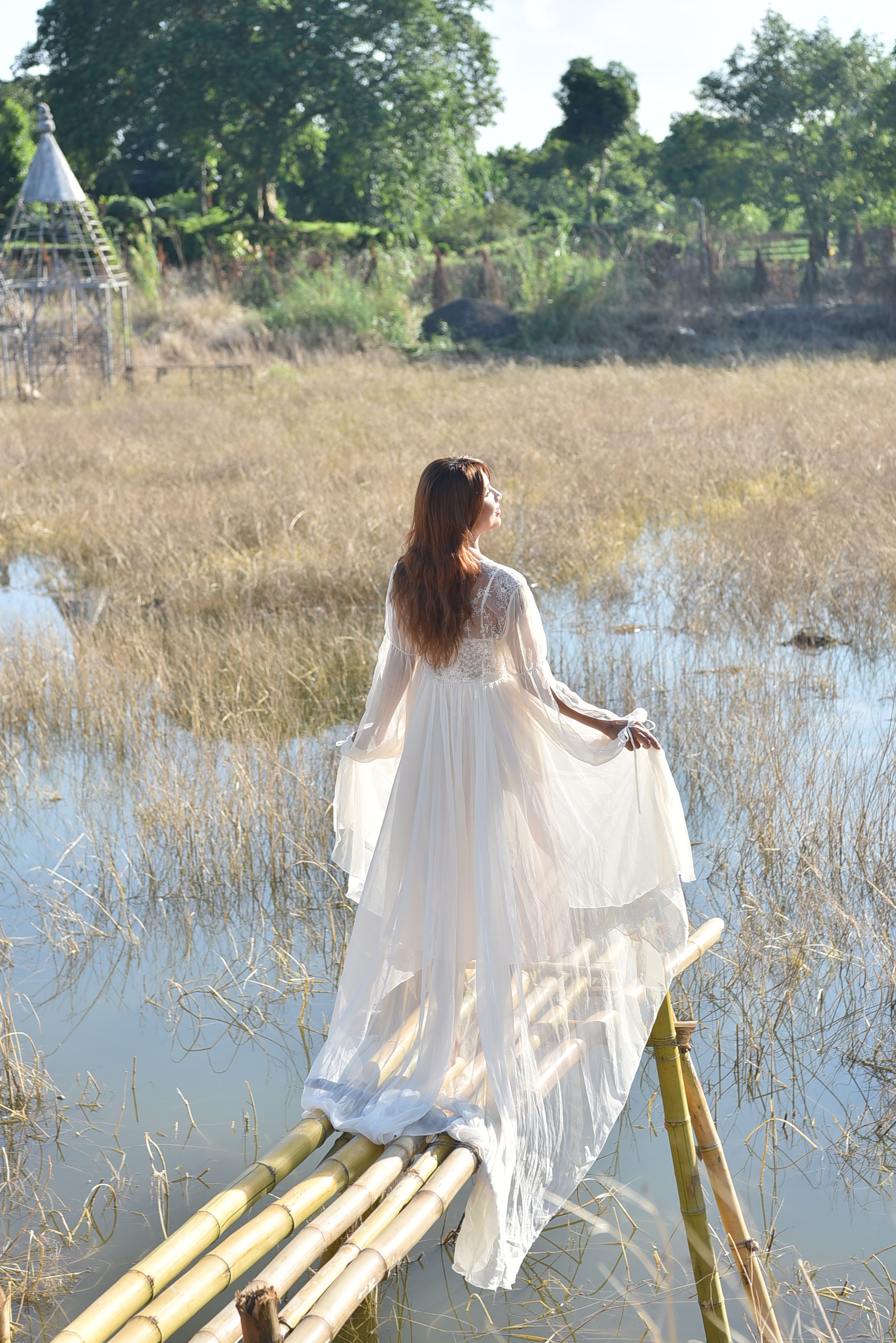 Elegant Woman in Flowing White Dress on Bamboo Bridge · Free Stock Photo