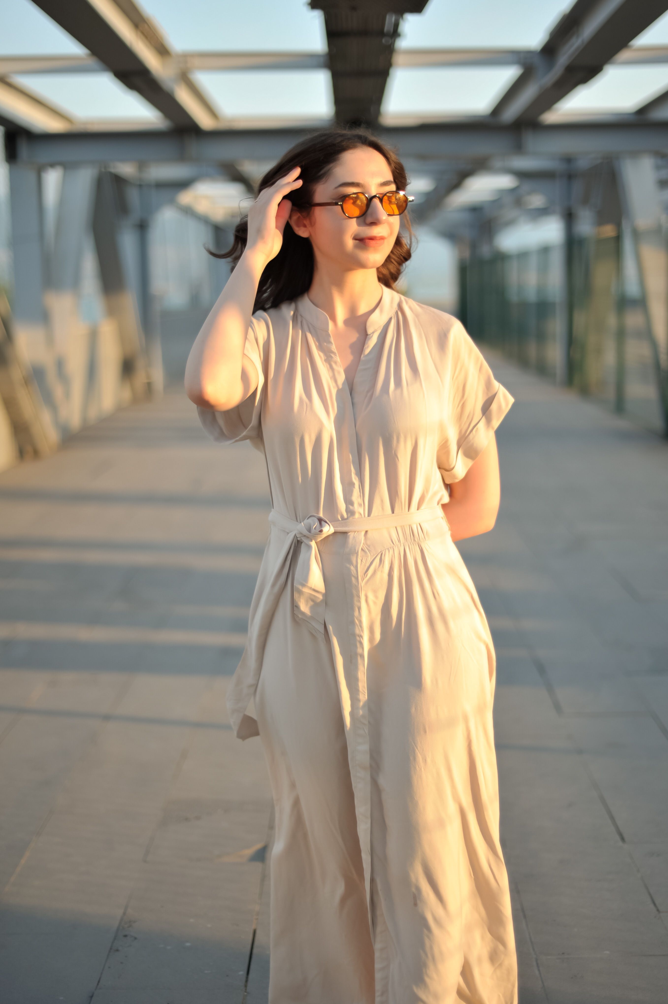 Woman in Flowing Dress Walking on Sunlit Bridge · Free Stock Photo