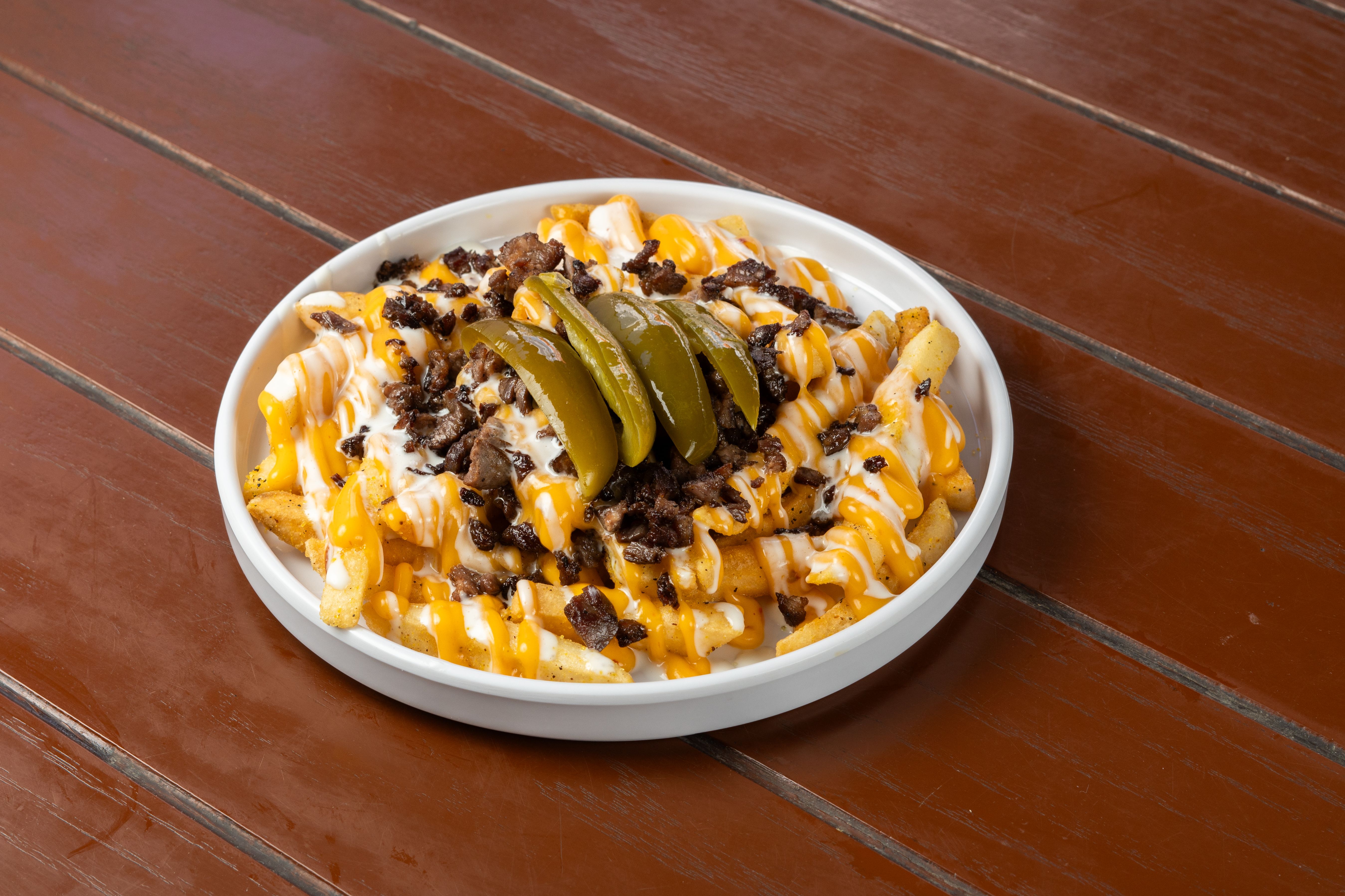 Loaded Fries with Cheese and Jalapeños on Wooden Table · Free Stock Photo