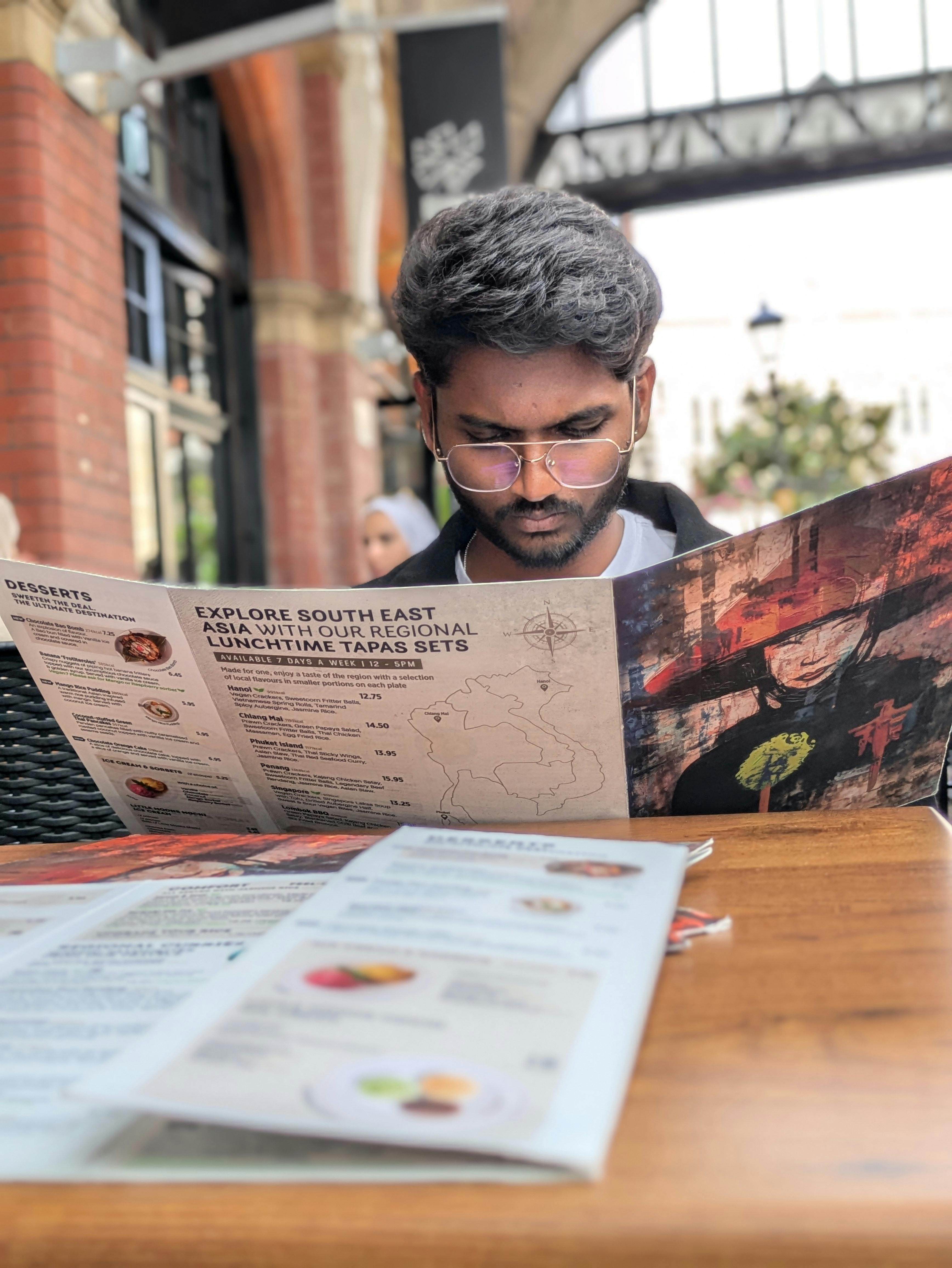 Man Reading Menu at Outdoor Cafe · Free Stock Photo