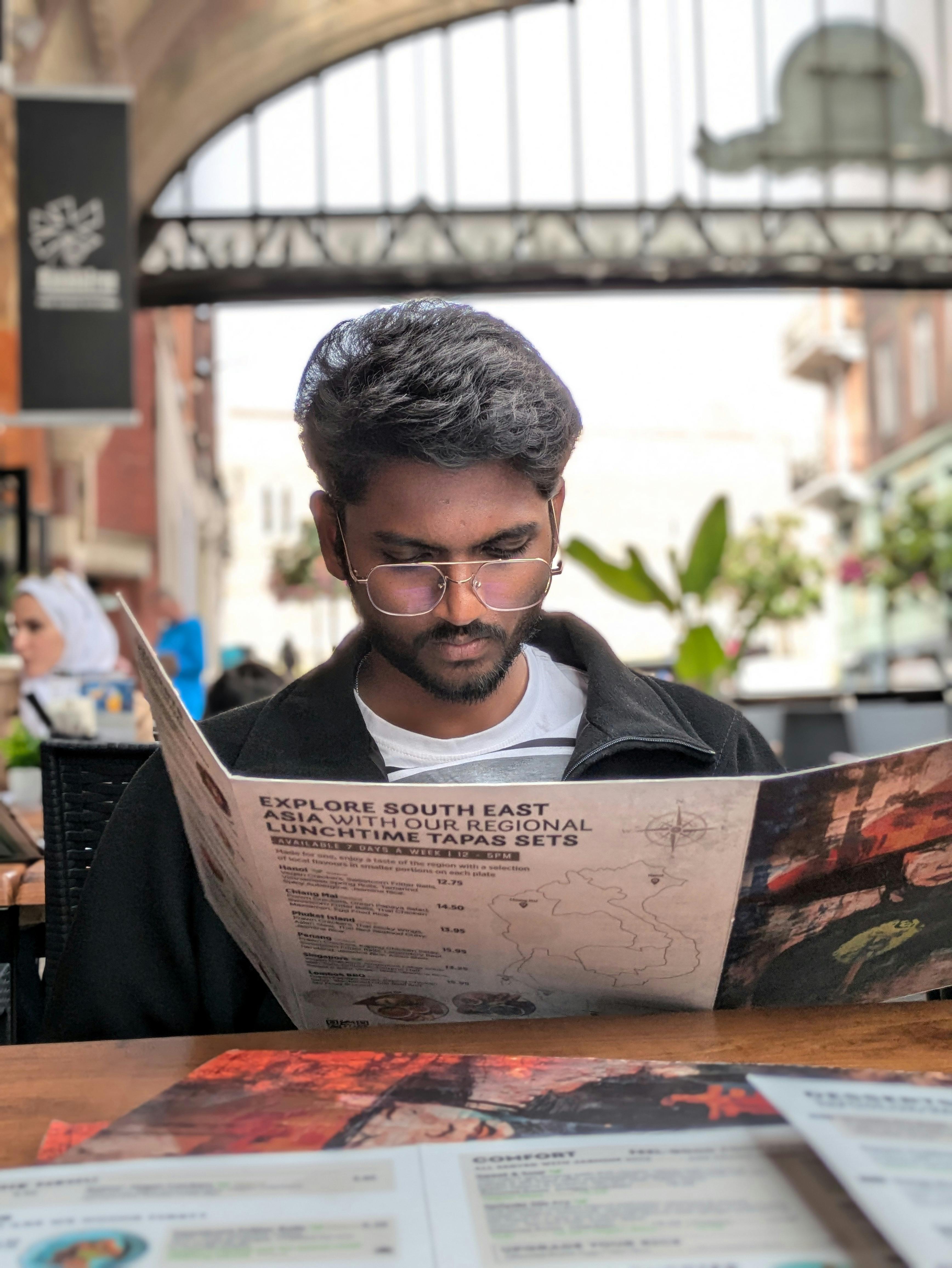 Man Reading Menu at Outdoor Cafe · Free Stock Photo