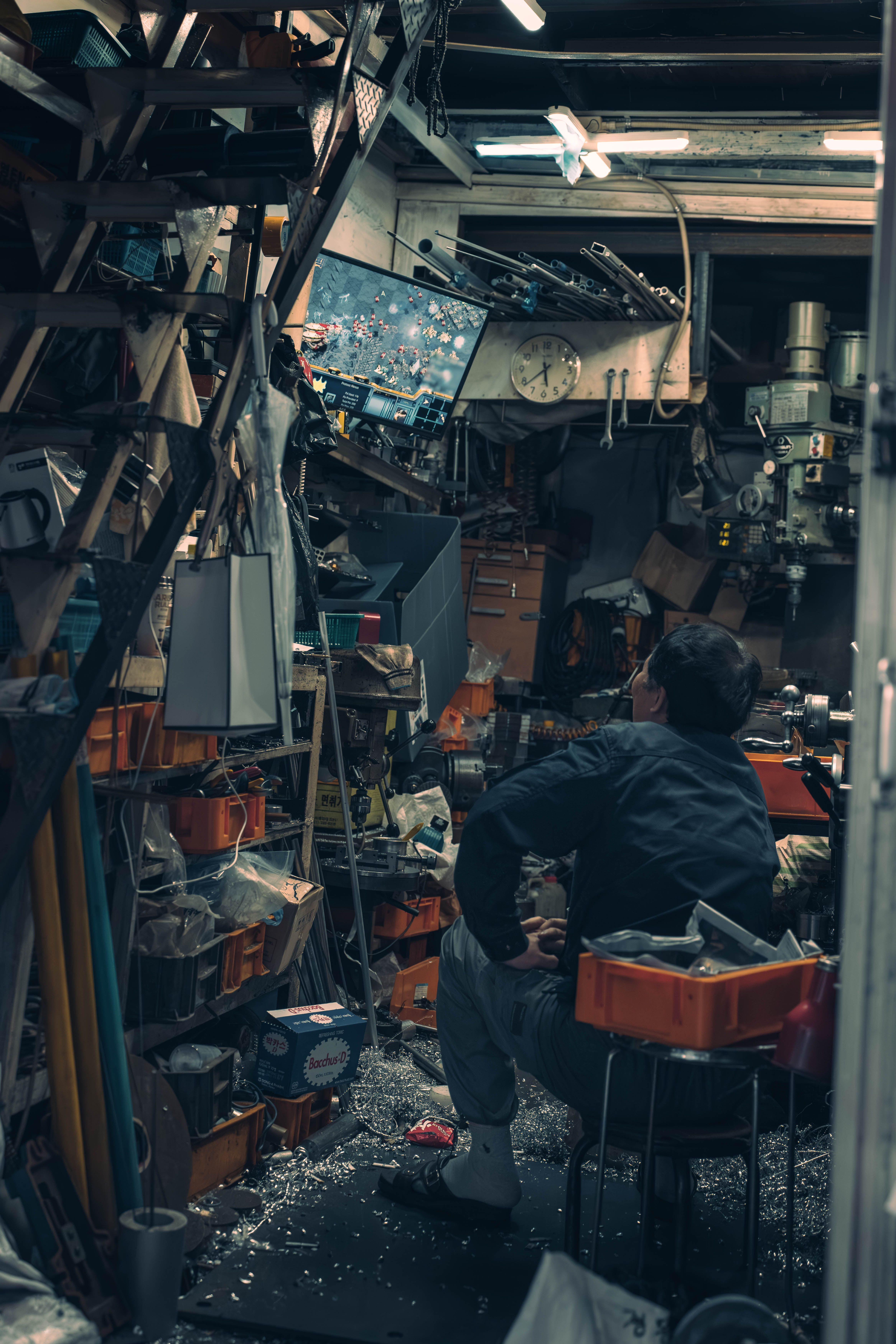 Man in Busy Workshop Surrounded by Tools · Free Stock Photo