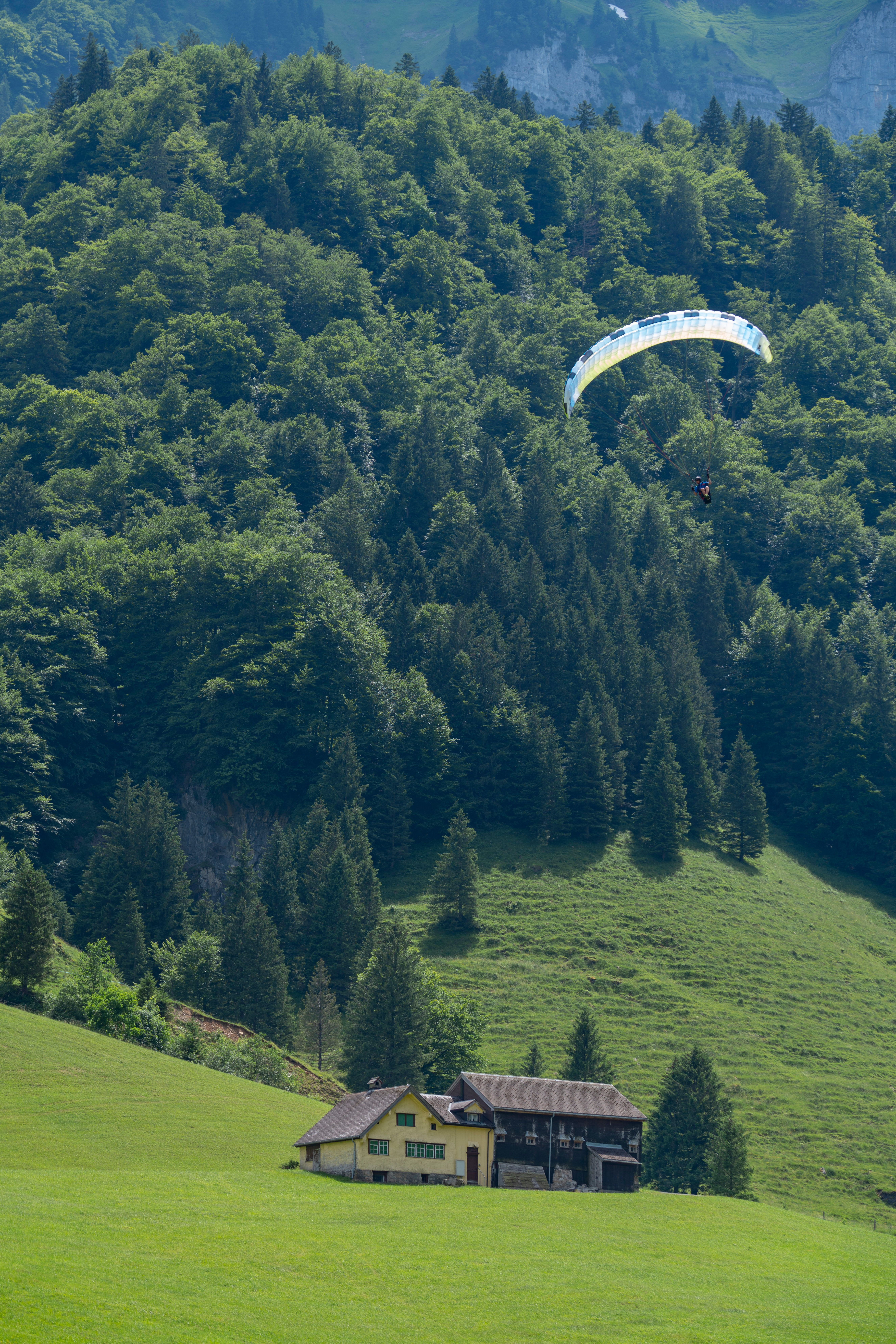Paraglider Over Scenic Mountain Cabin · Free Stock Photo