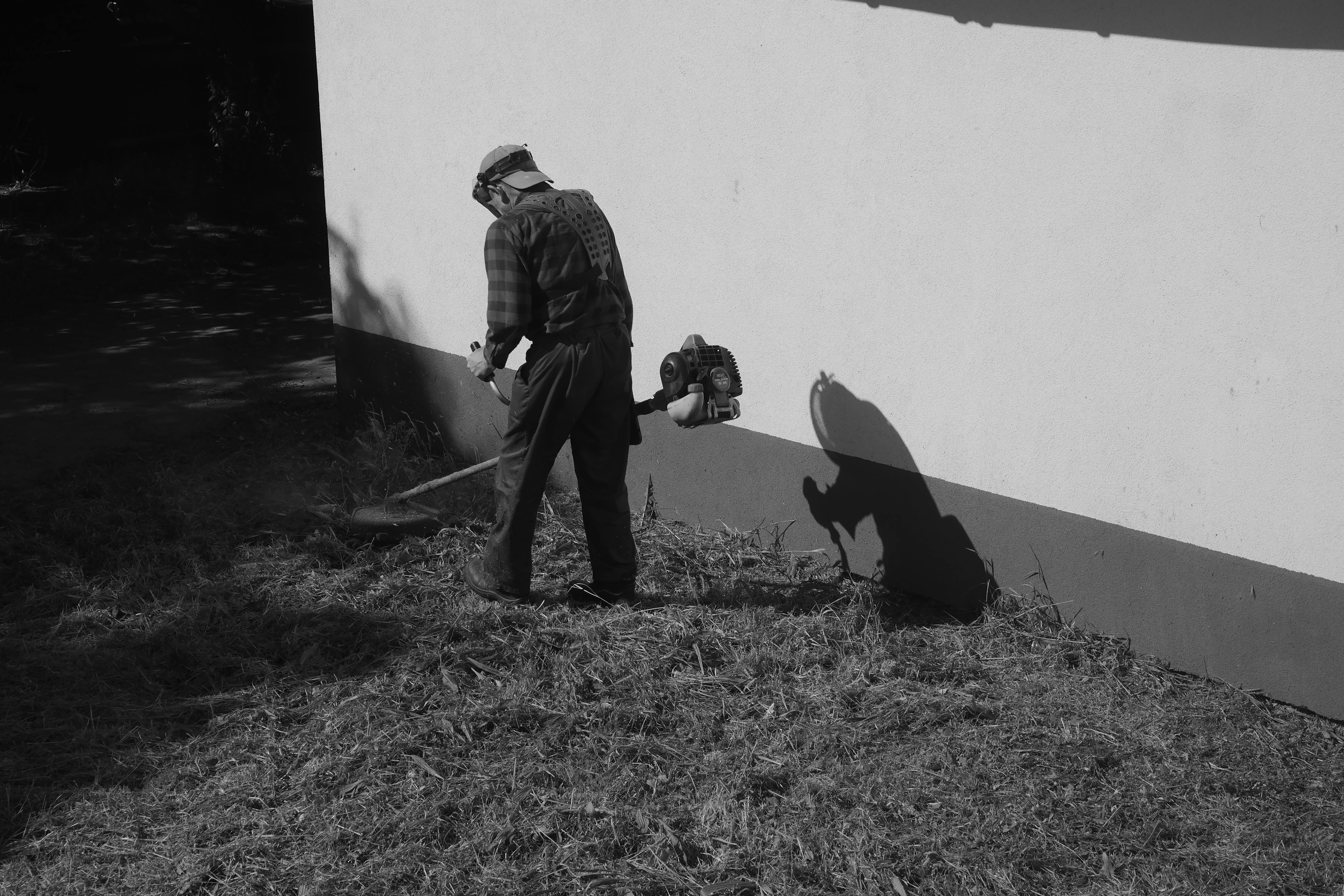 Man Trimming Grass with Weed Whacker in Black and White · Free Stock Photo