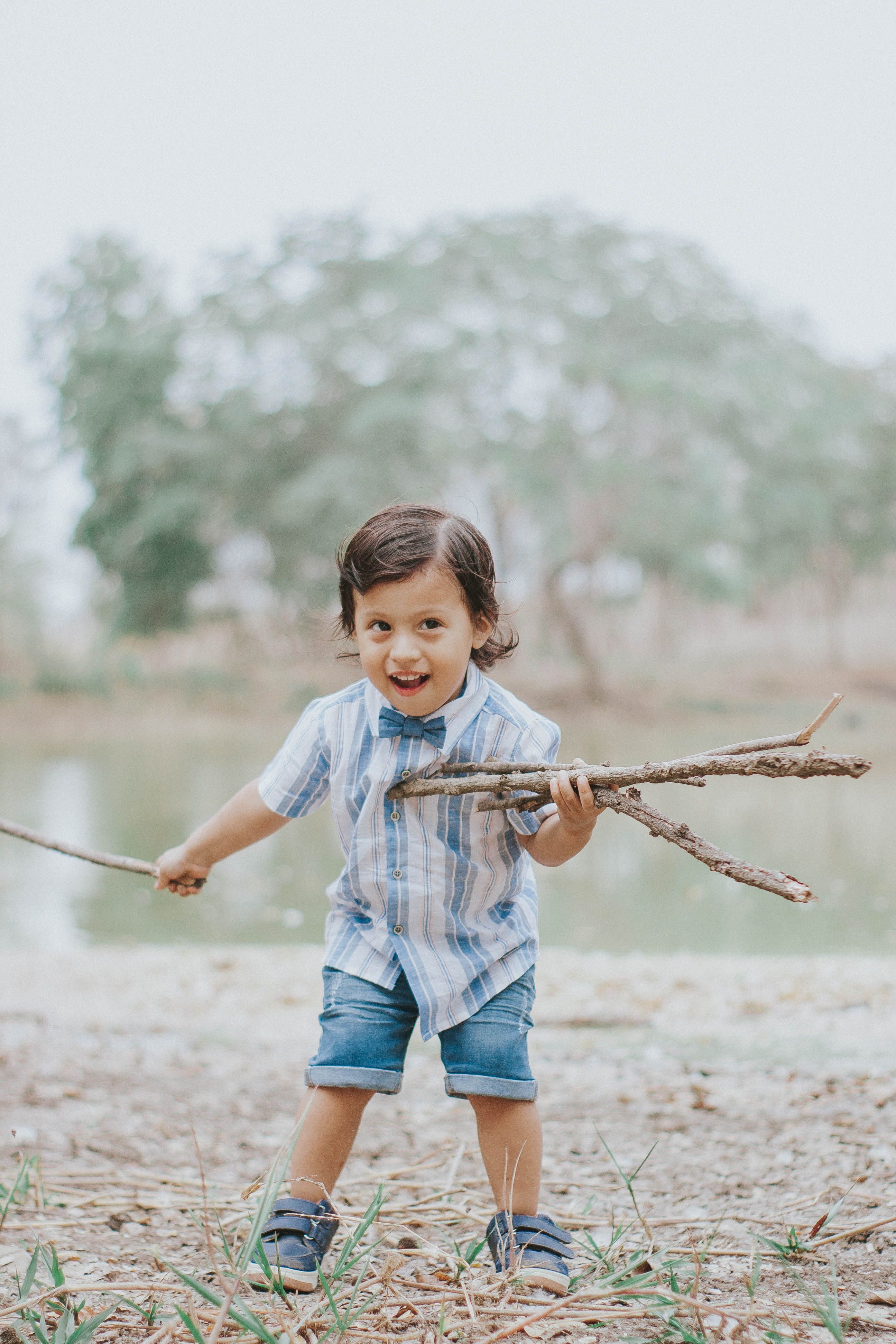 Joyful Child Playing with Sticks Outdoors · Free Stock Photo