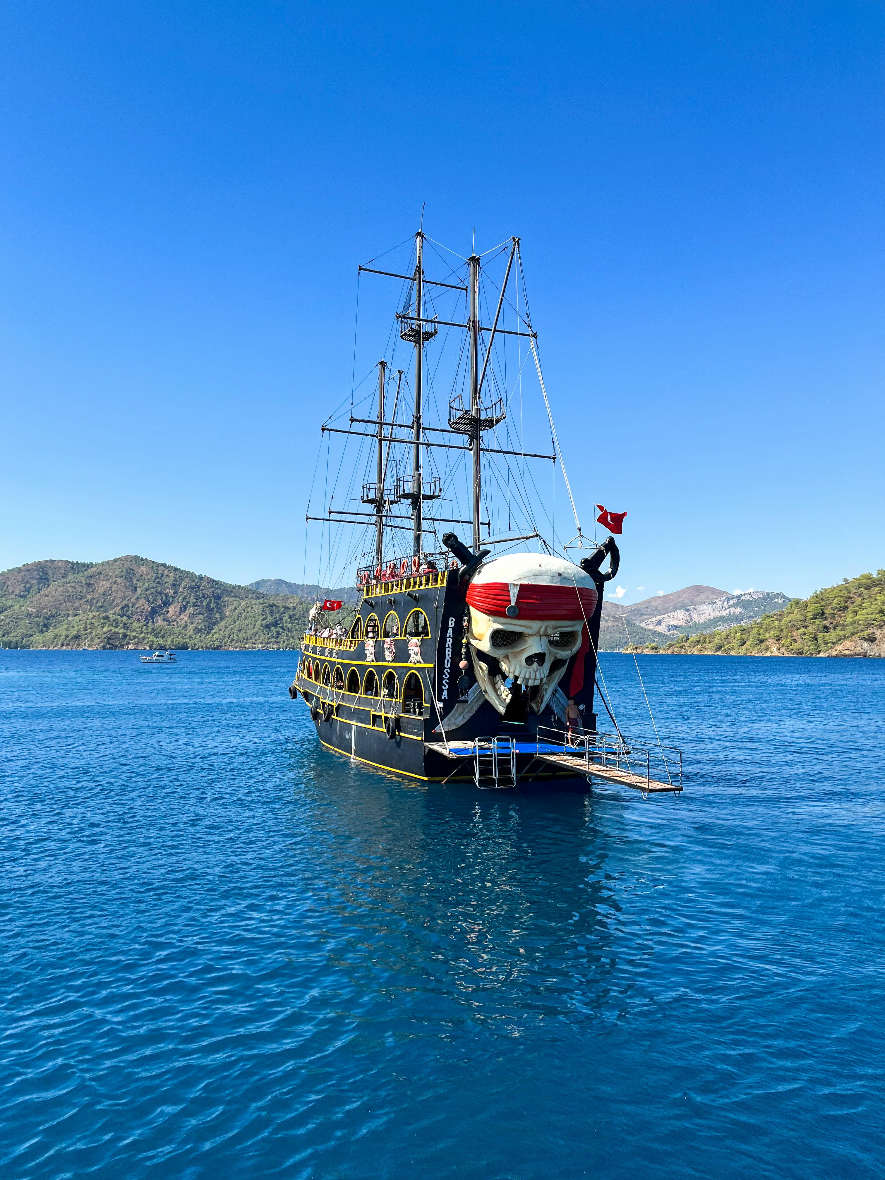 Pirate Ship in Turquoise Waters Near Mountains · Free Stock Photo