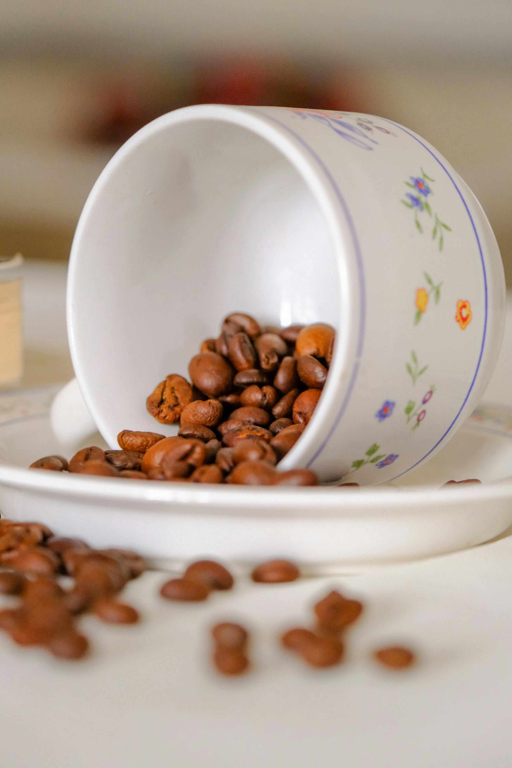 Spilled Coffee Beans in a Floral Mug · Free Stock Photo