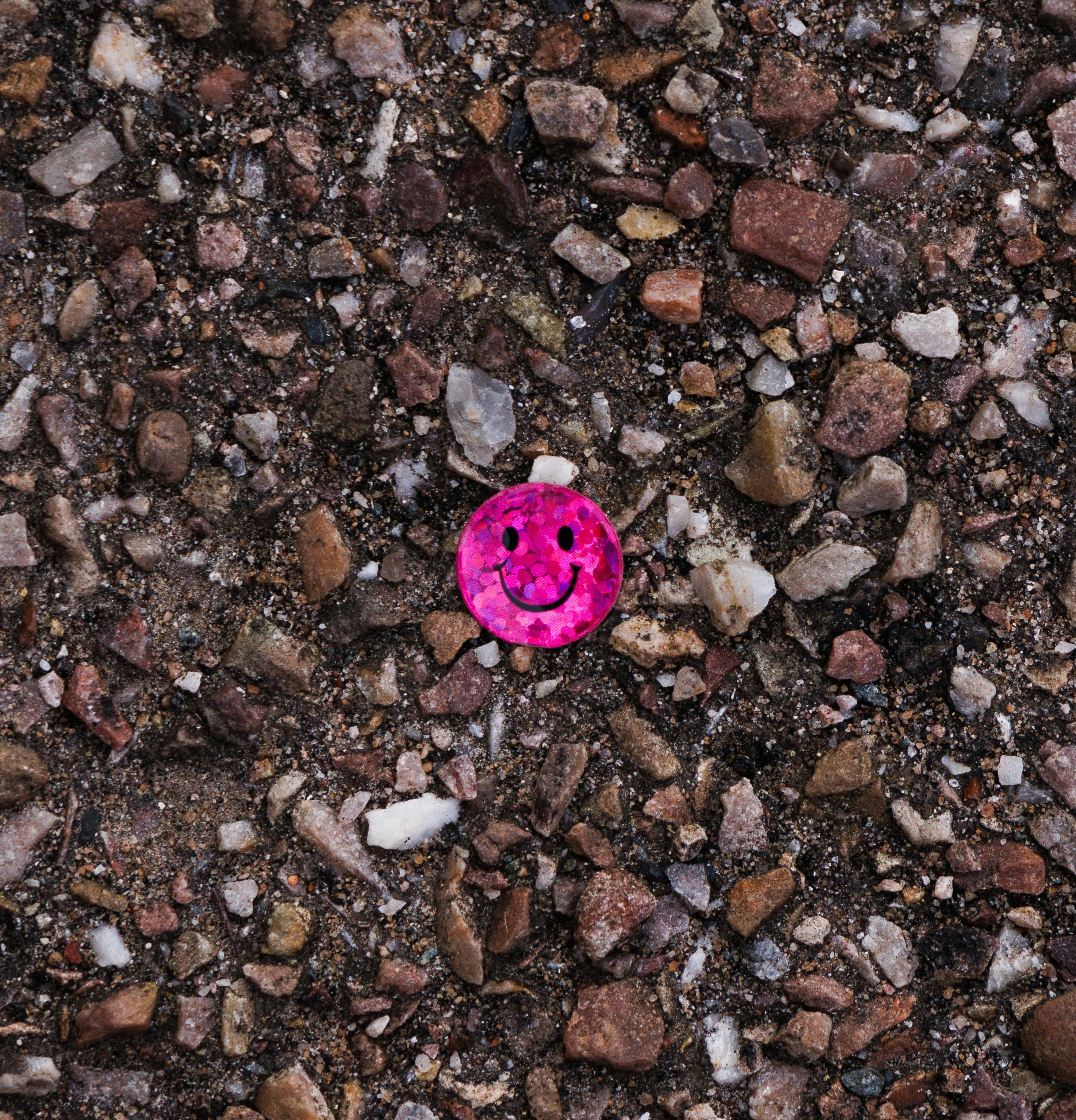 Pink Smiley Sticker on Rocky Gravel Background · Free Stock Photo