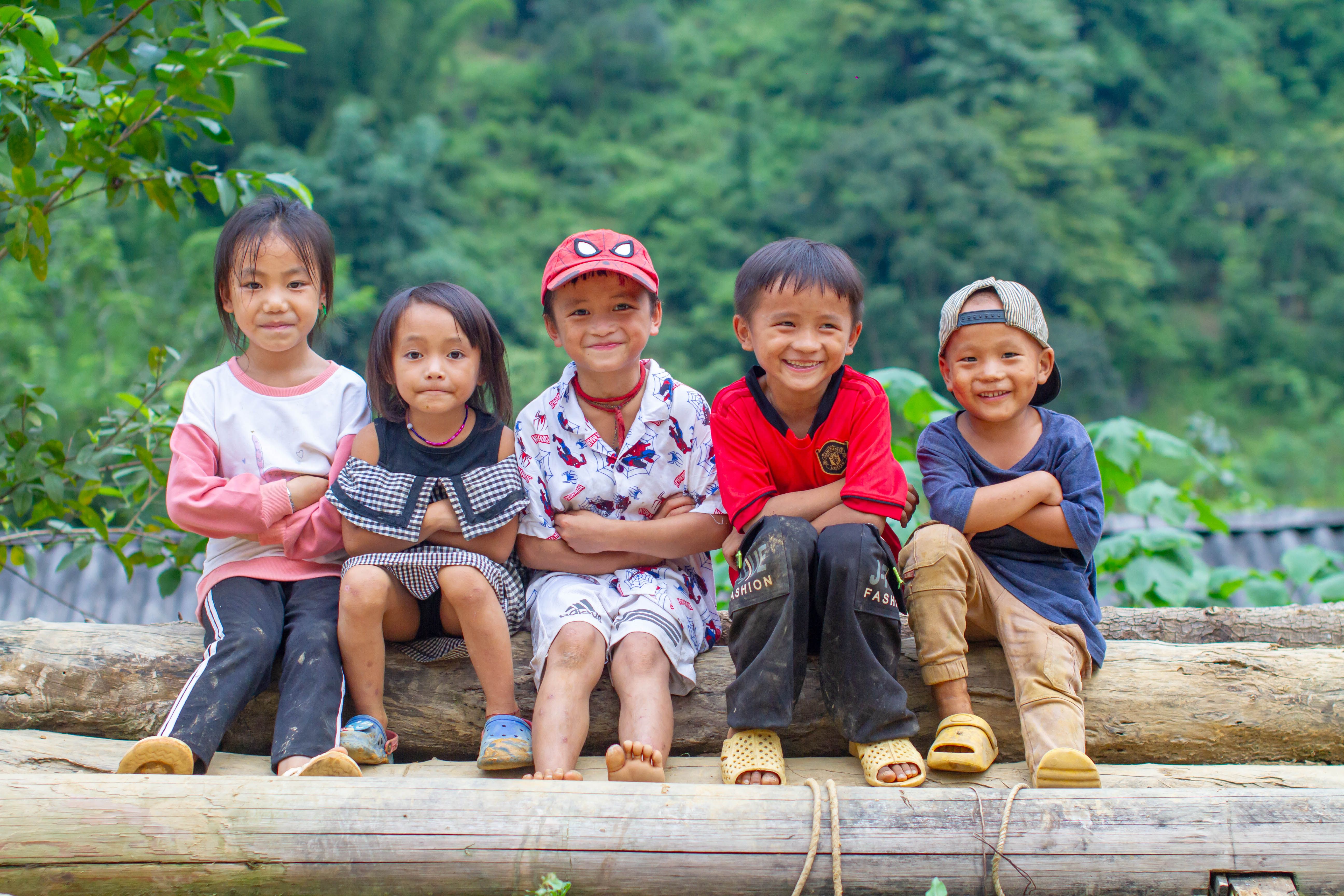 Joyful Group of Kids Sitting Outdoors on Logs · Free Stock Photo