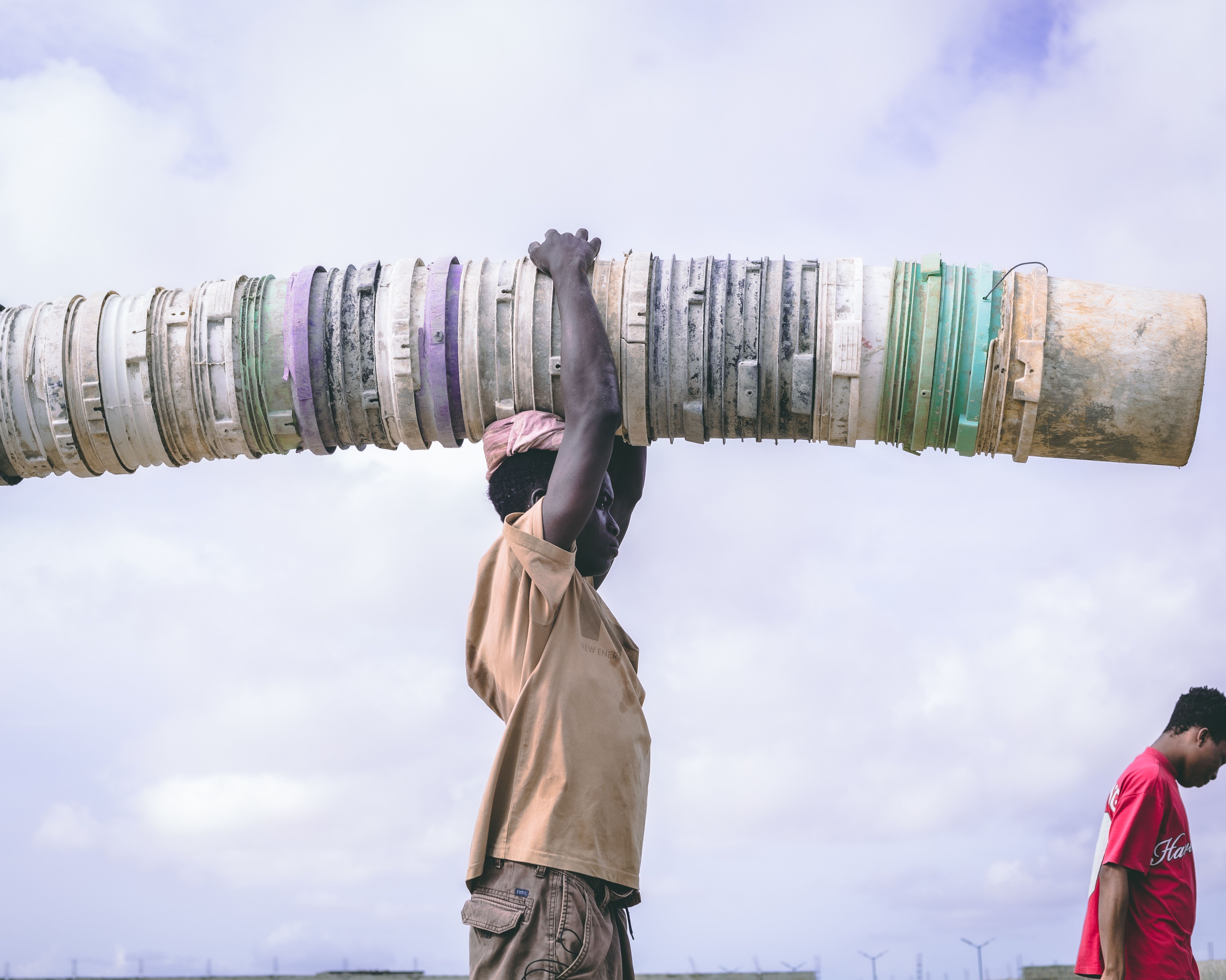Man carrying large pipe outdoors in rural setting · Free Stock Photo