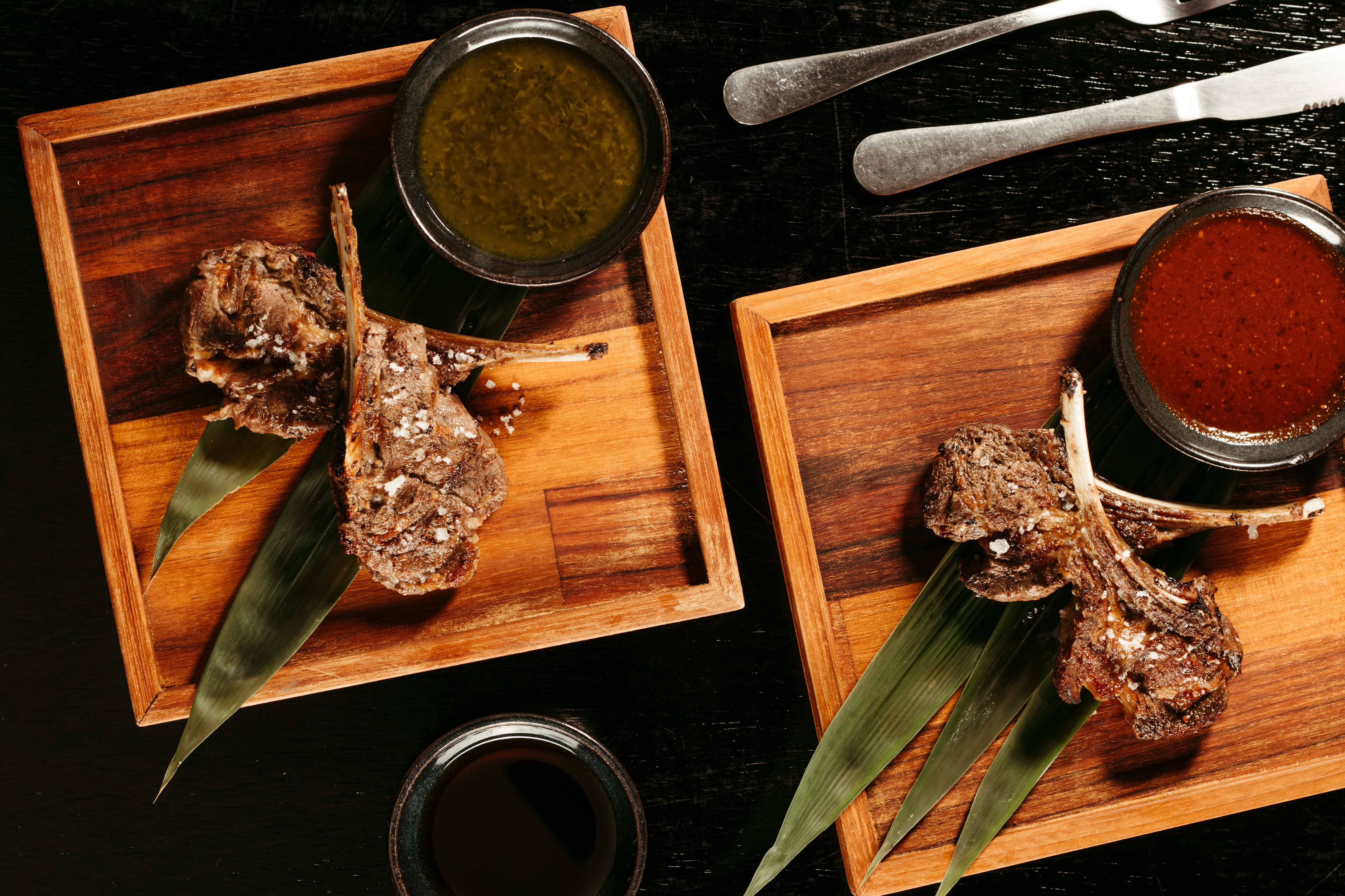 Gourmet Lamb Chops with Sauces on Wooden Platters · Free Stock Photo