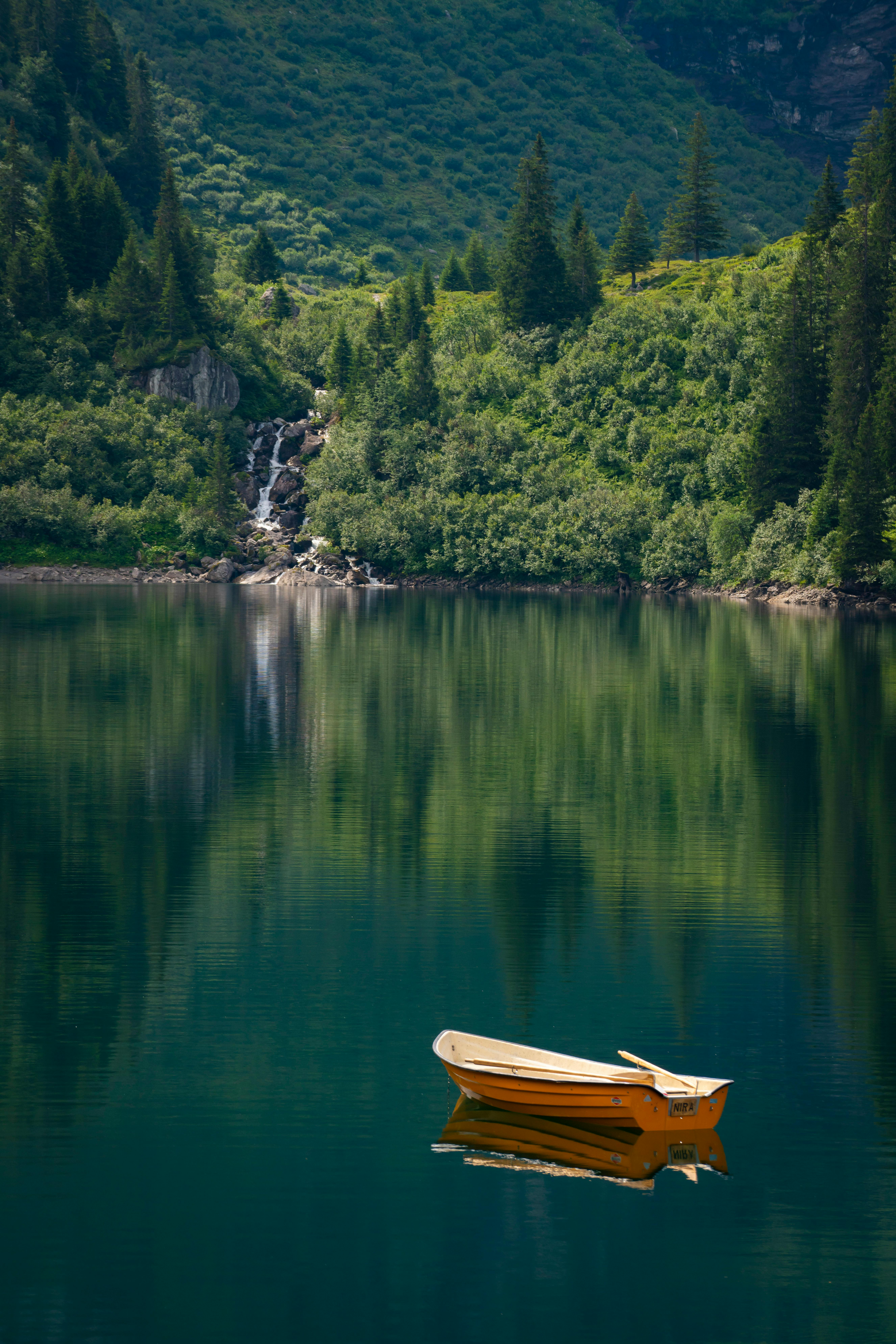 Tranquil Lake with Yellow Rowboat and Waterfall · Free Stock Photo