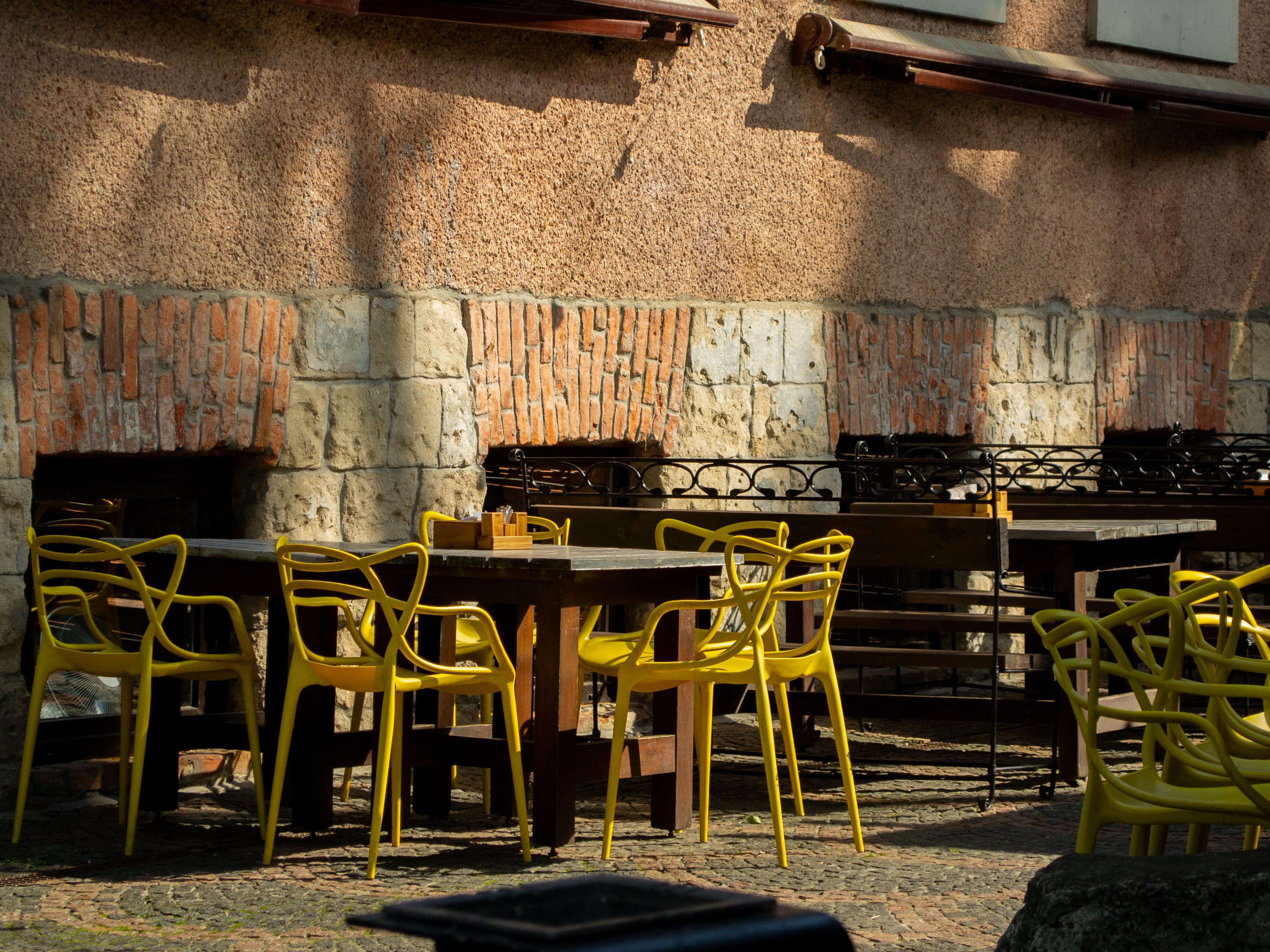 Outdoor Cafe with Yellow Chairs and Rustic Wall · Free Stock Photo