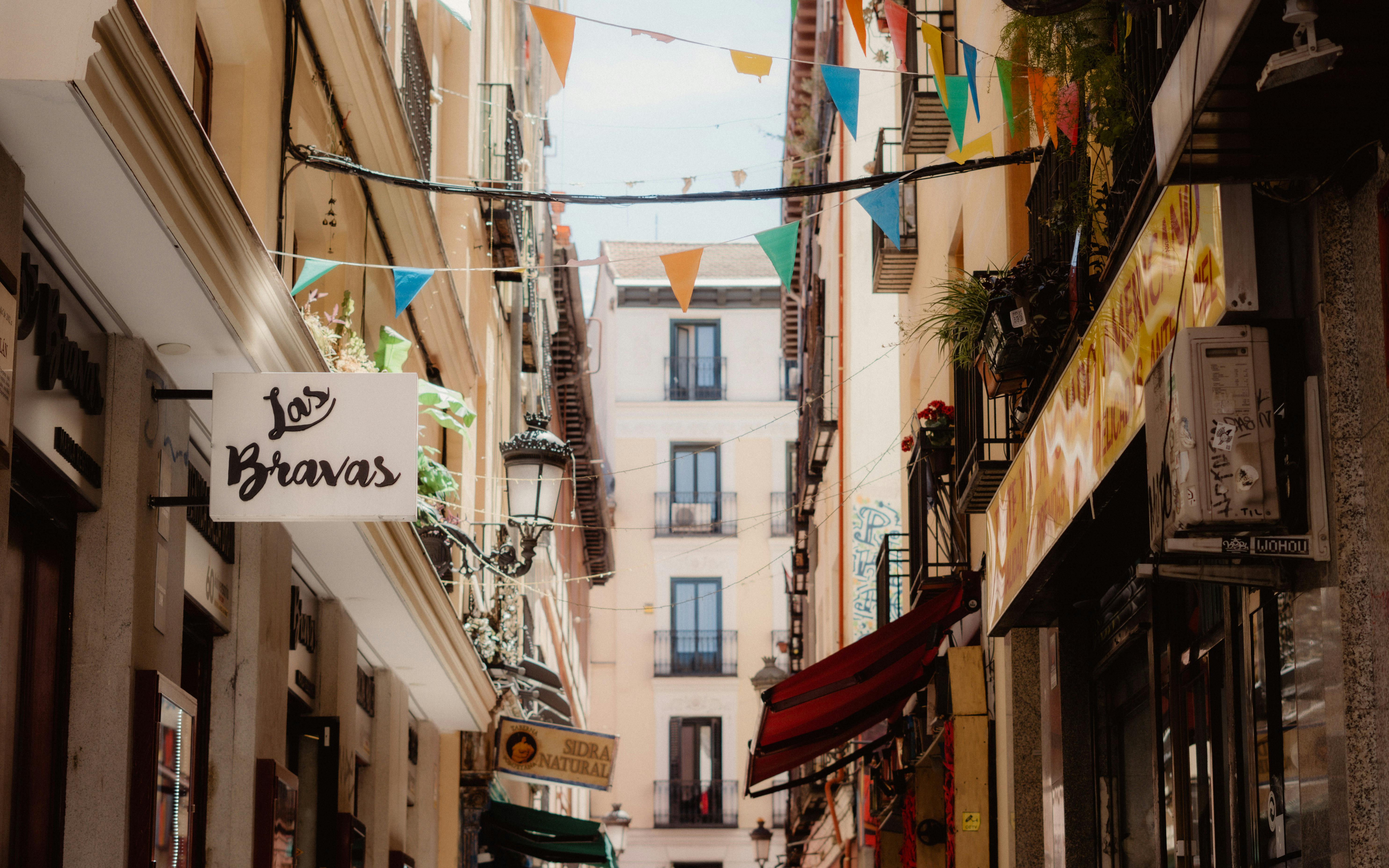 Colorful Alleyway in Madrid with Flags and Storefronts · Free Stock Photo