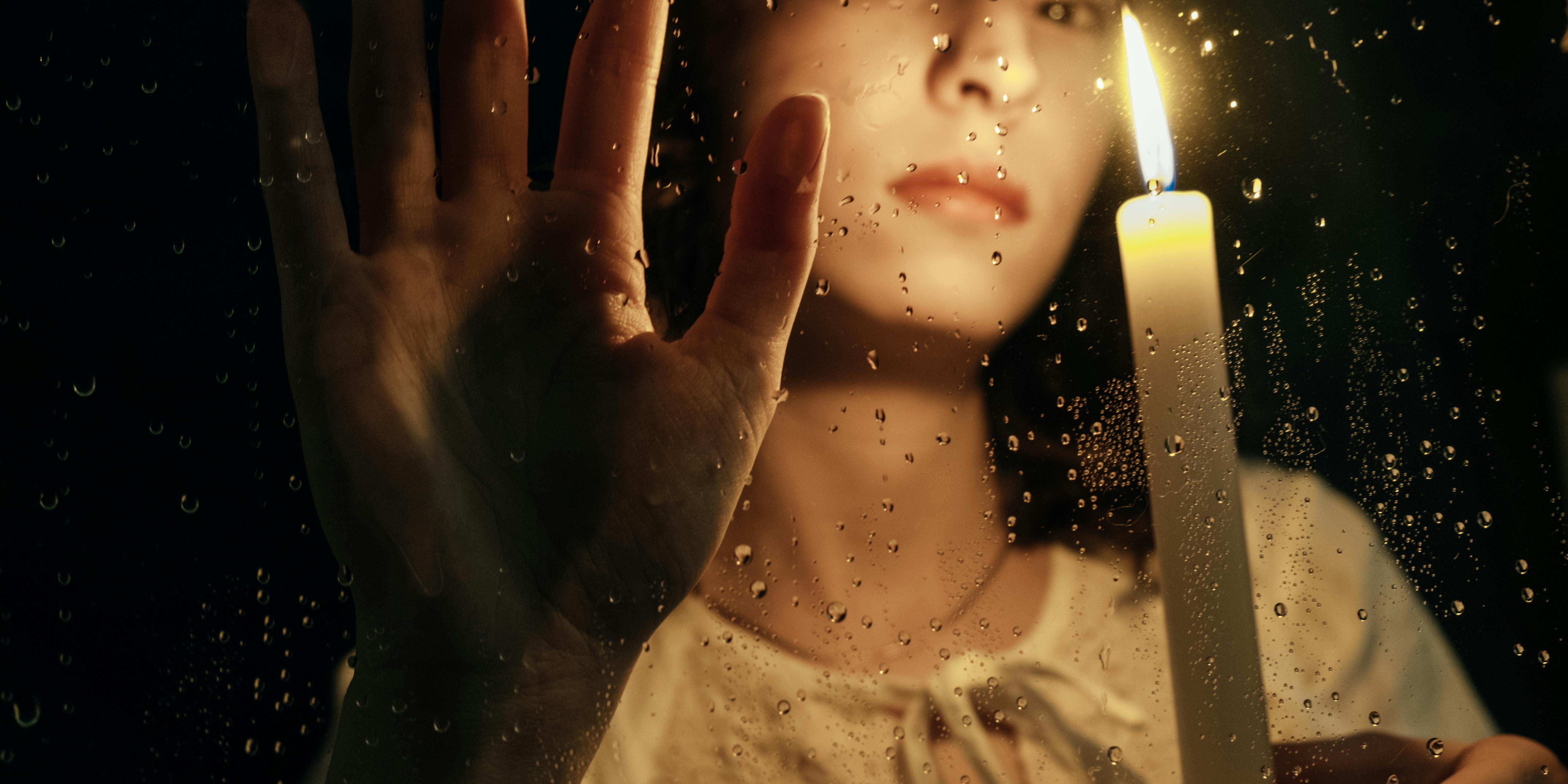 Reflective Woman Holding Candle in Rainy Atmosphere · Free Stock Photo