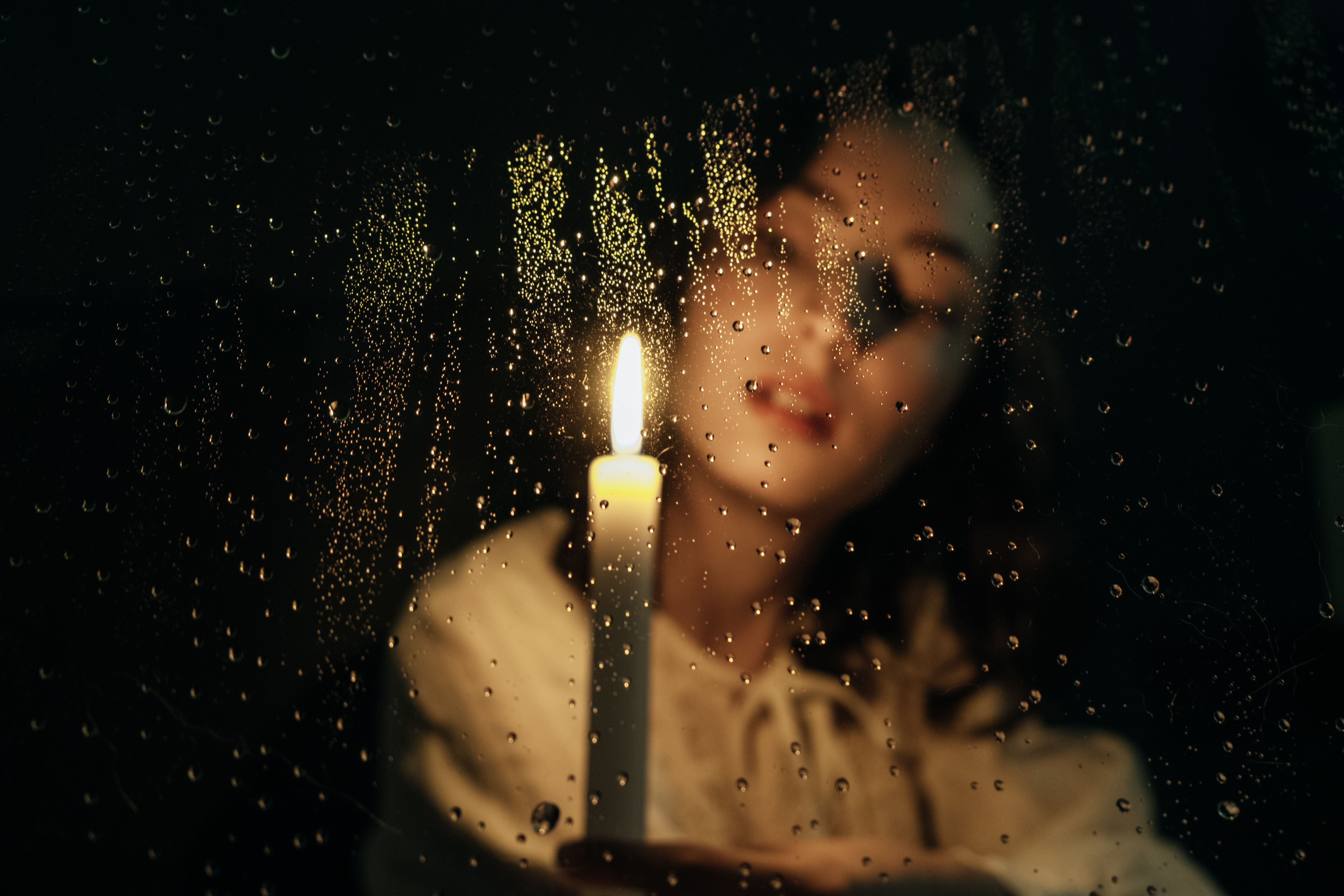 Candlelit Portrait Behind Raindrop Glass · Free Stock Photo