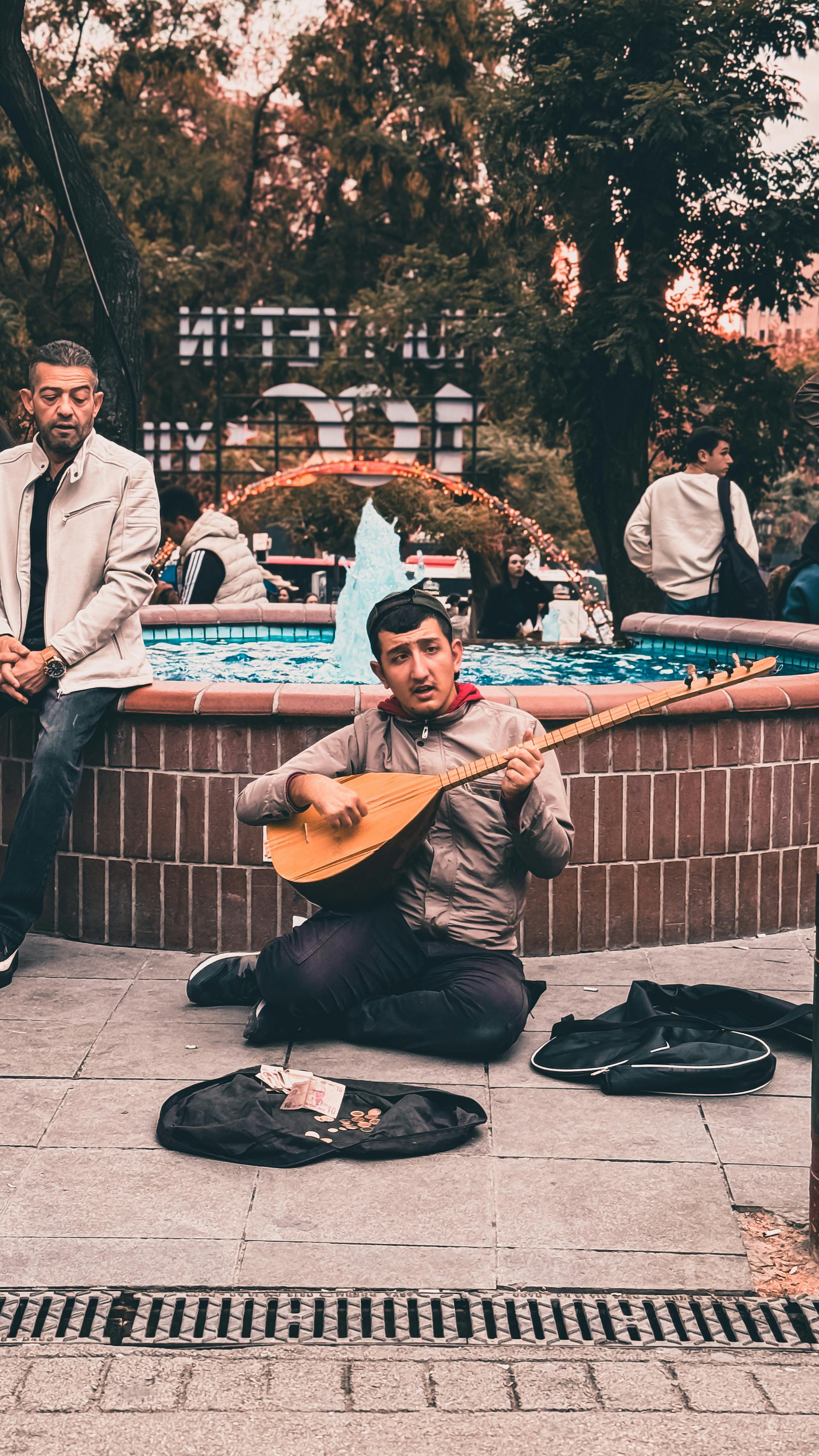 Street Musician Playing Saz by Fountain in Autumn · Free Stock Photo