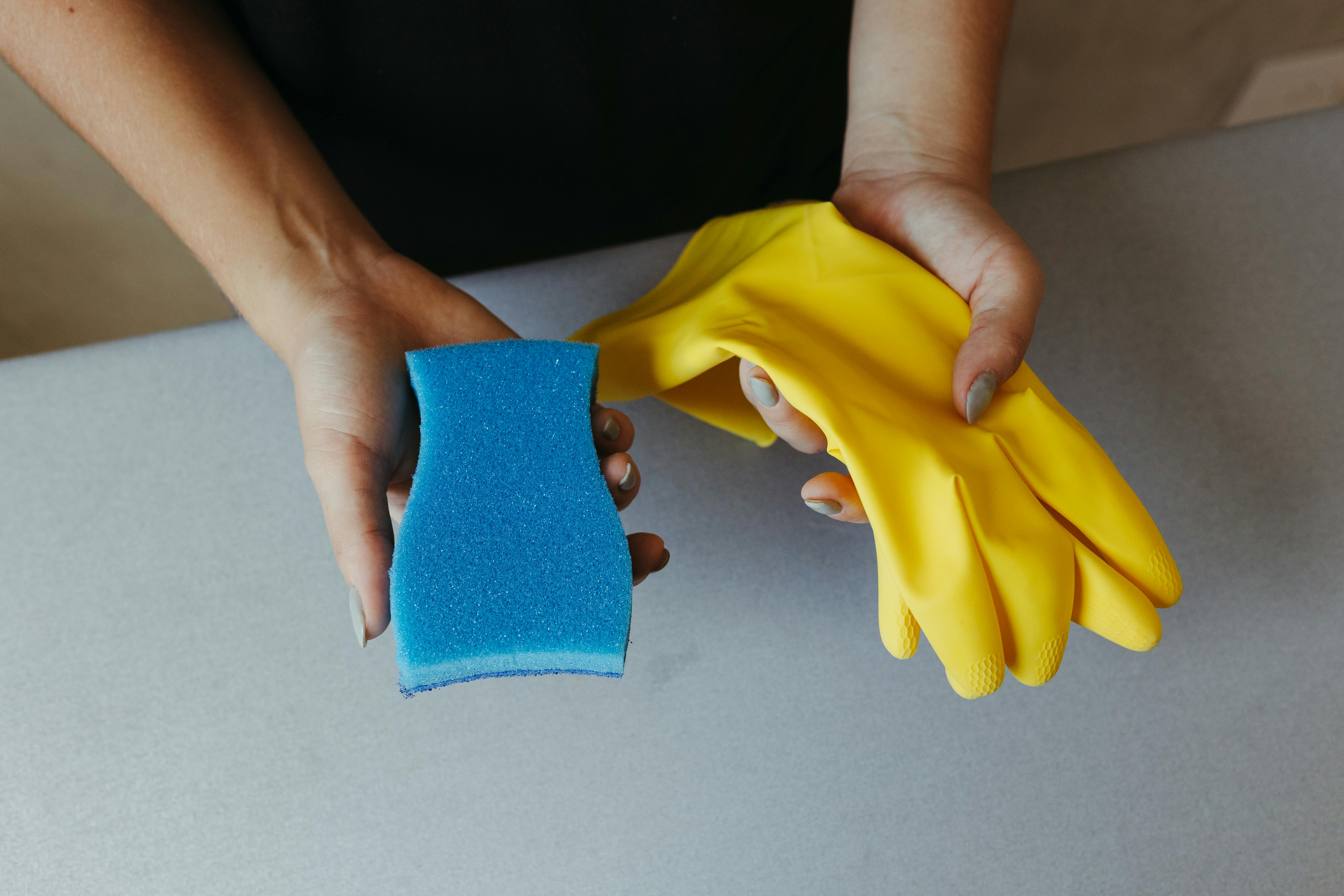 Crop faceless person in rubber glove squeezing sponge · Free Stock Photo