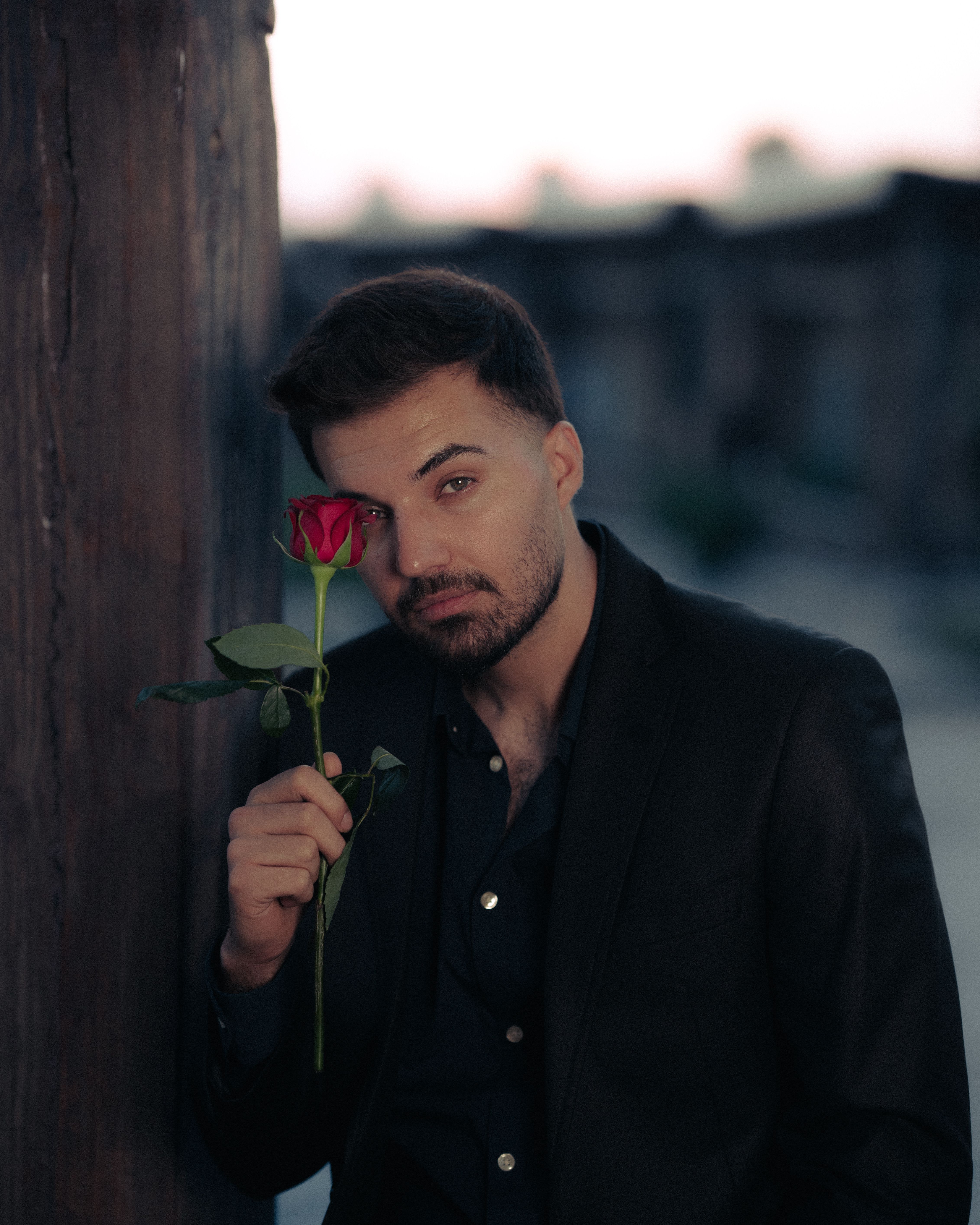Man Posing with a Red Rose Outdoors at Dusk · Free Stock Photo