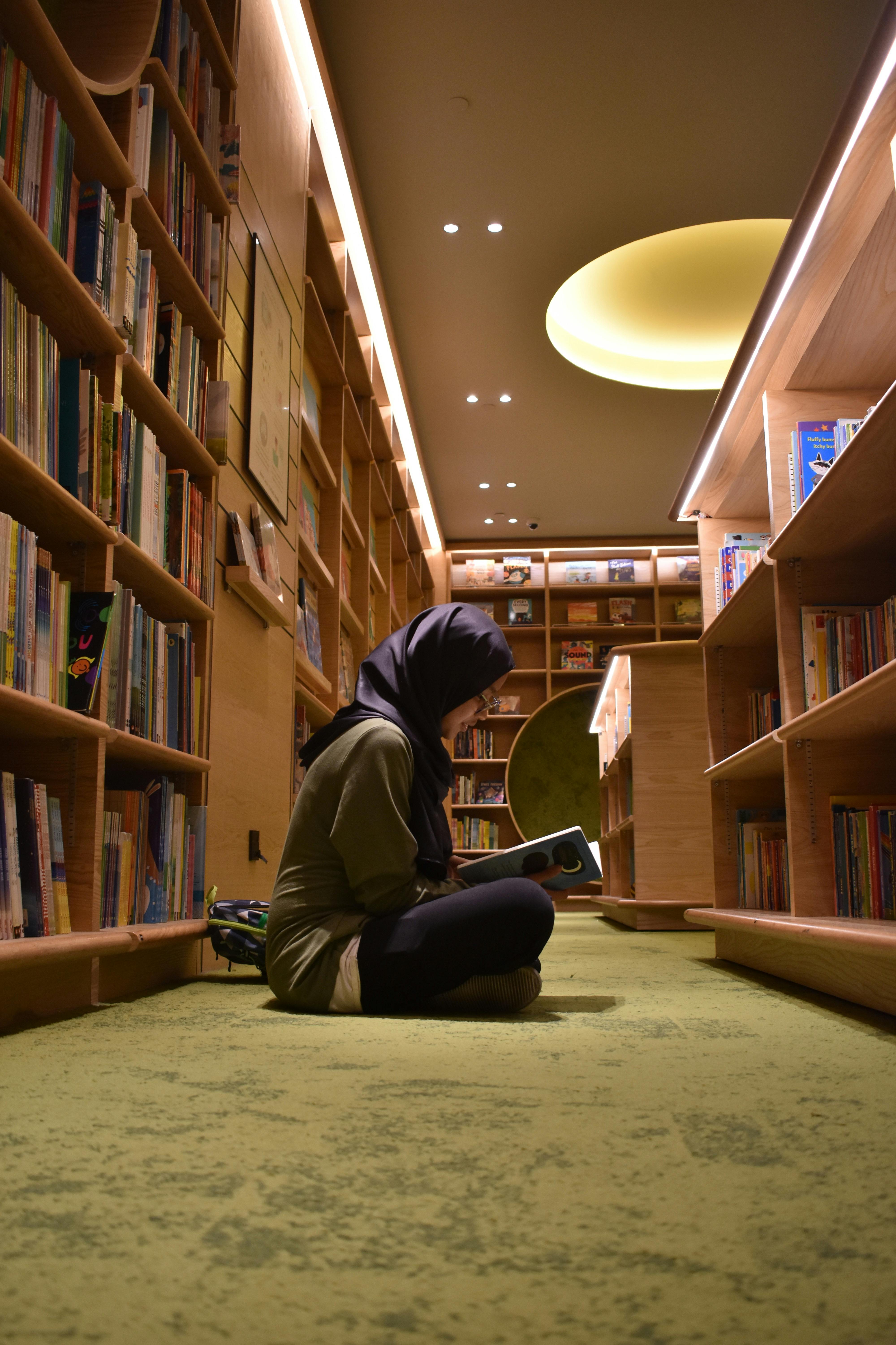 Man Standing Inside Library While Reading Book · Free Stock Photo