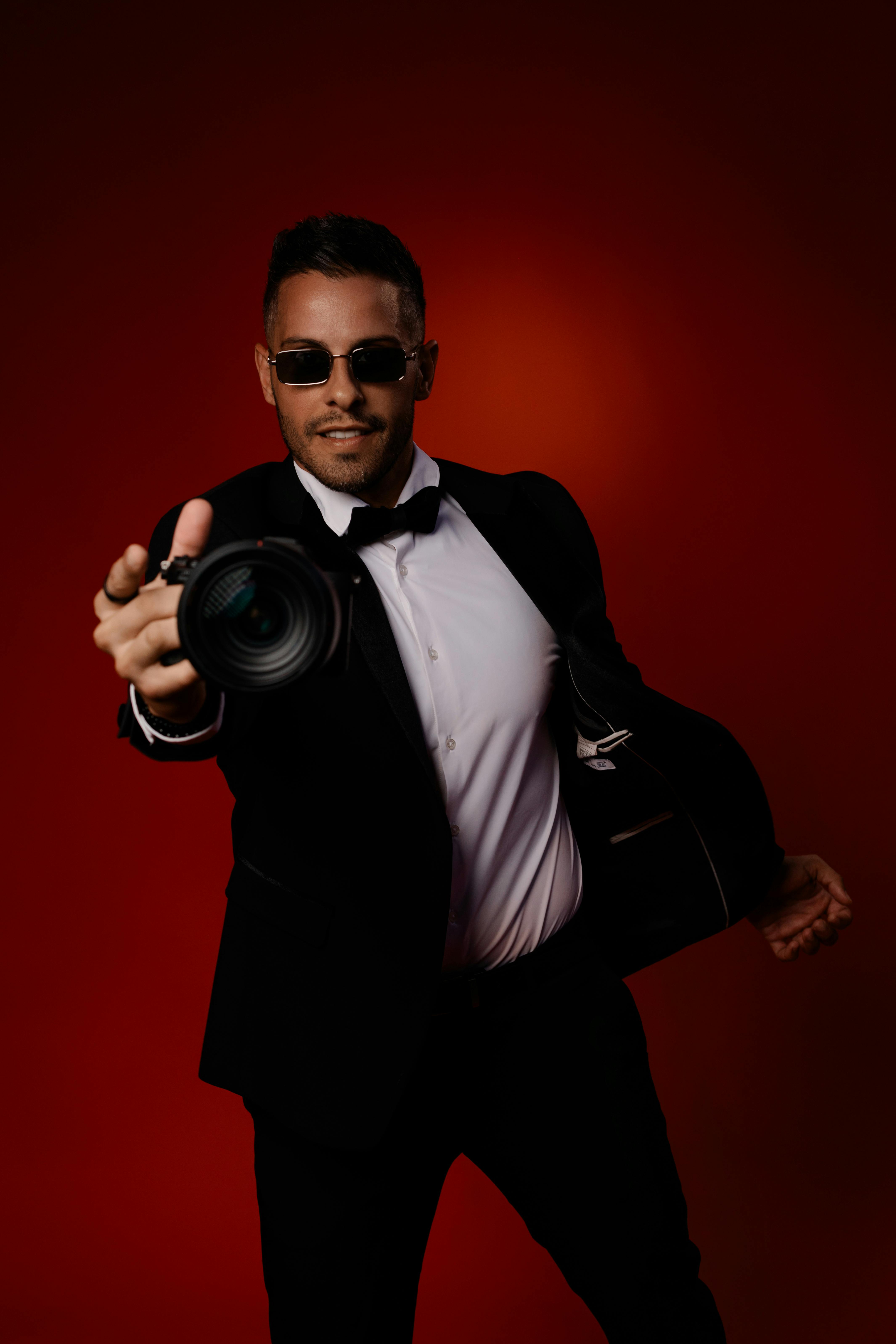 Confident Photographer in Stylish Suit Holding Camera · Free Stock Photo