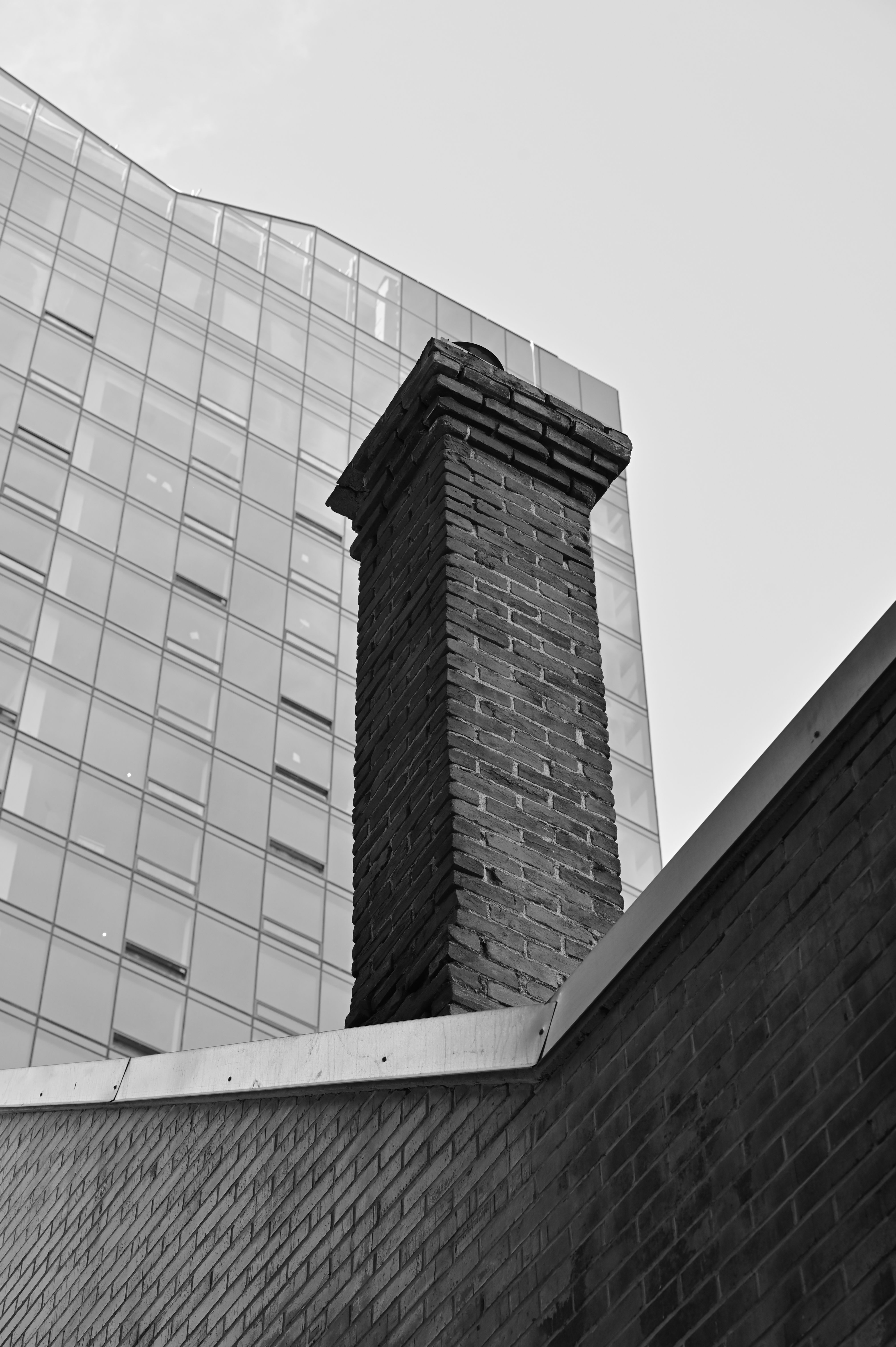 Urban Contrast with Brick Chimney and Modern Building · Free Stock Photo