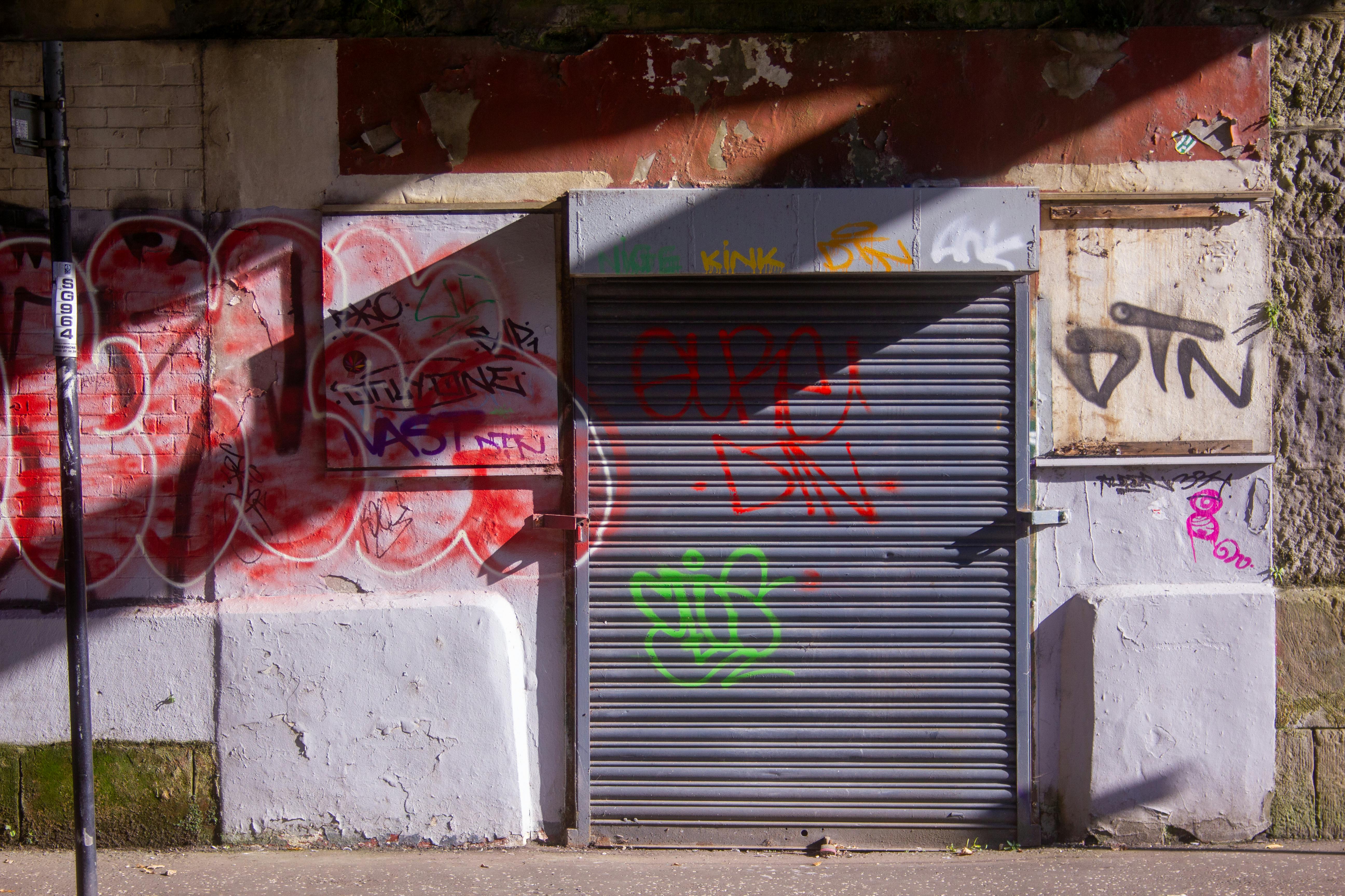 Urban Graffiti on Shuttered Storefront Doorway · Free Stock Photo