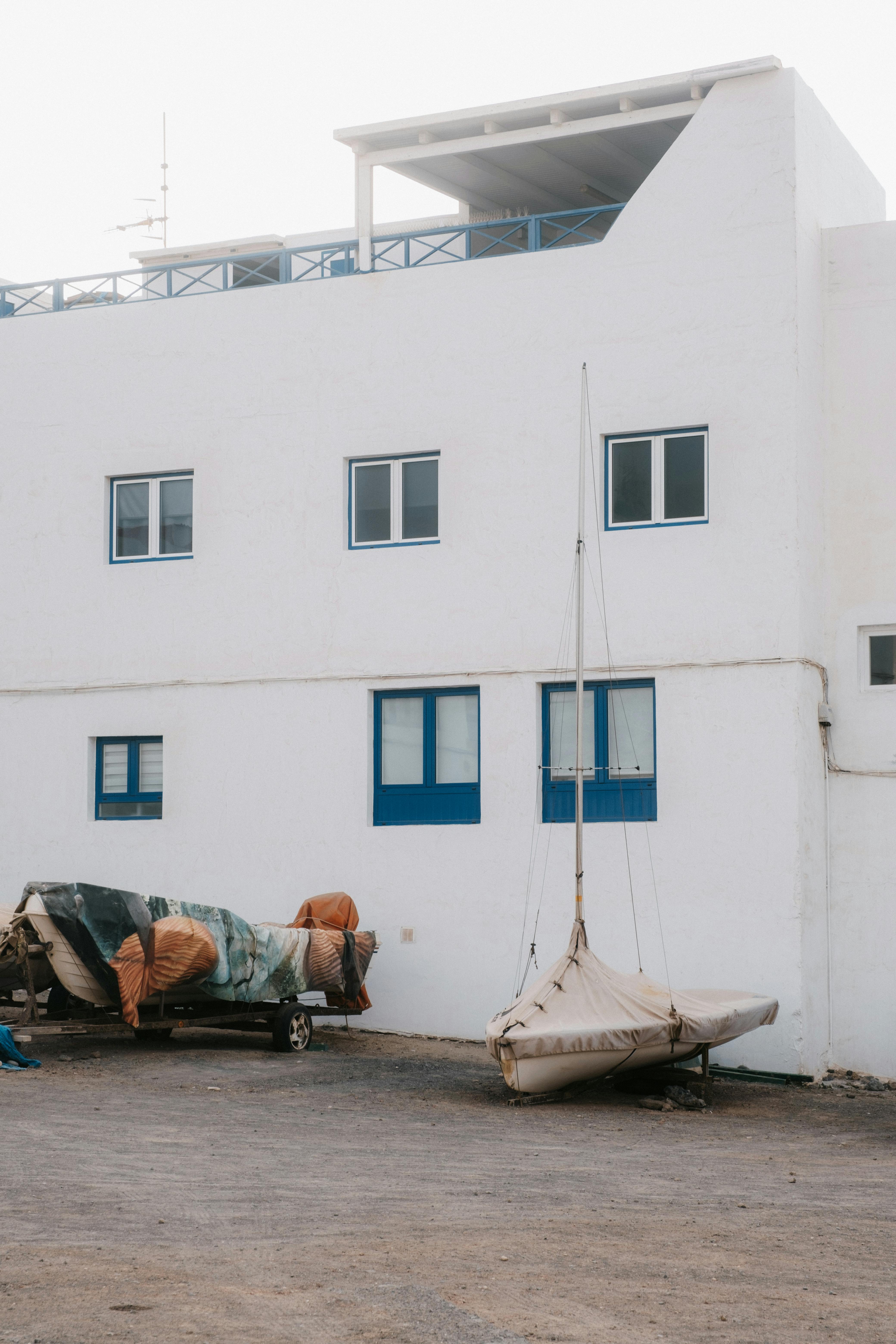 White Building with Blue Windows in Coastal Town · Free Stock Photo
