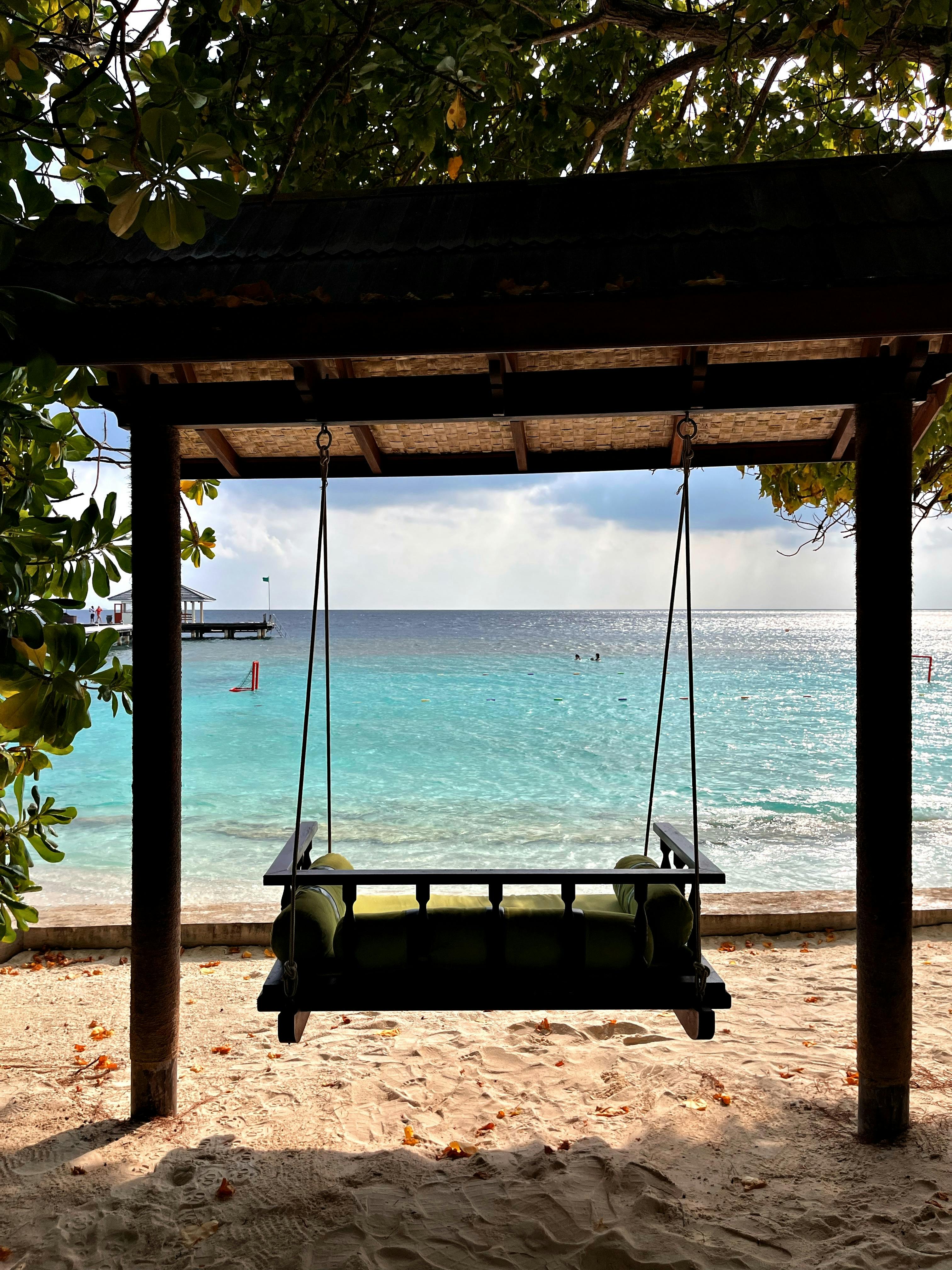 Serene Beachfront Swing Overlooking Turquoise Sea · Free Stock Photo