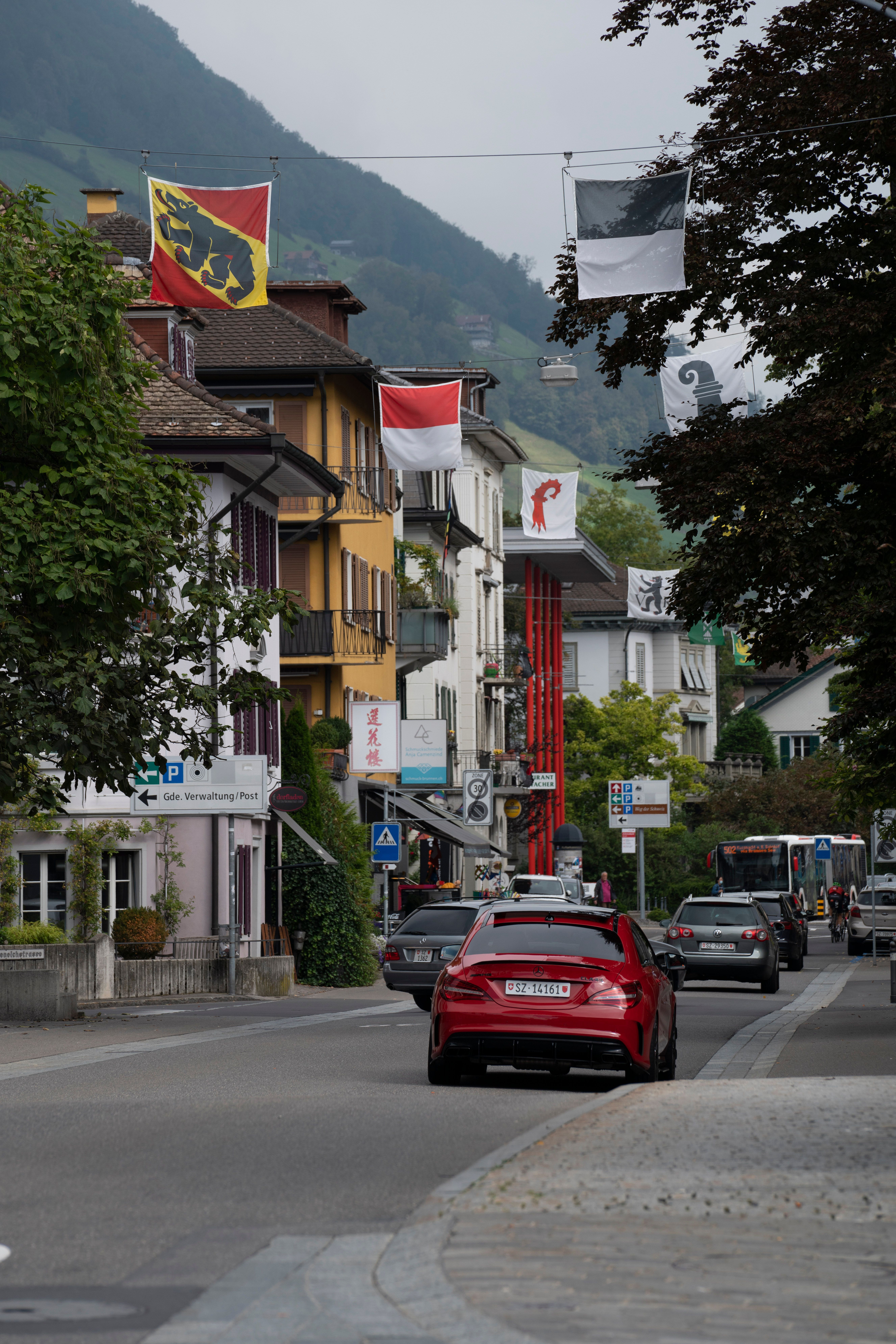 Street Scene in Swiss Town with Flags and Cars · Free Stock Photo