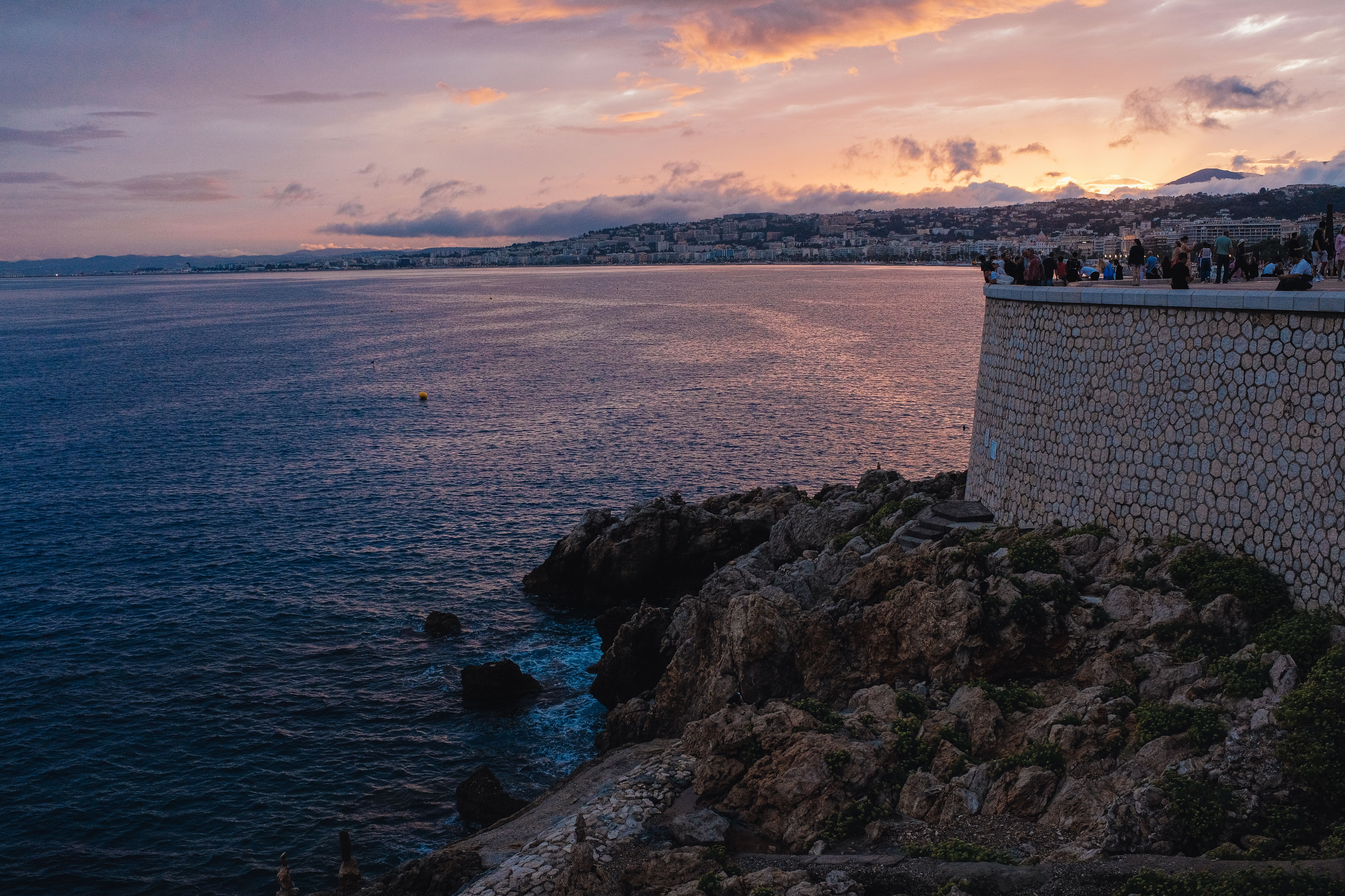 Sunset View Over Rocky Coastline and City Skyline · Free Stock Photo