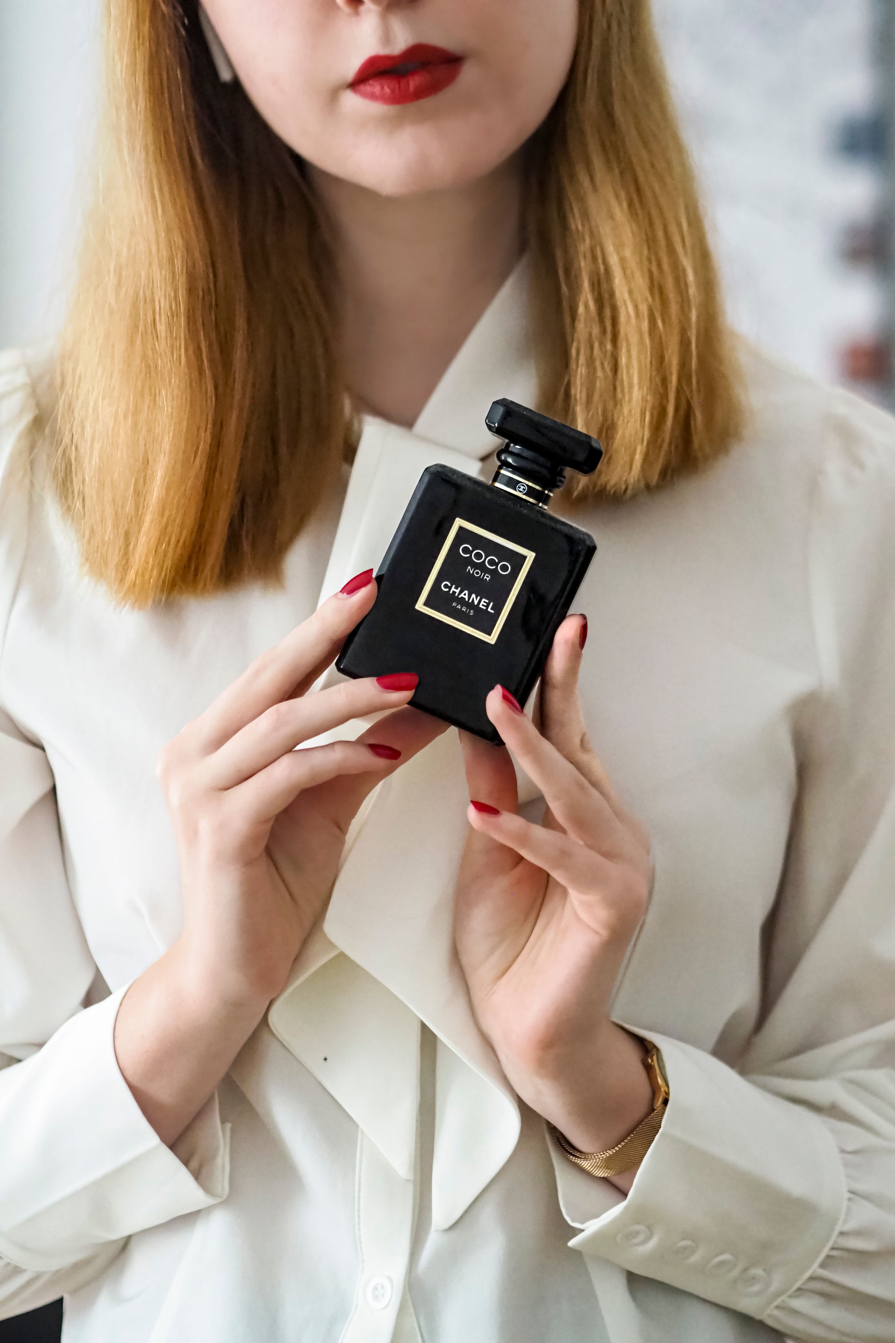Elegant Woman Holding Perfume Bottle Indoors · Free Stock Photo