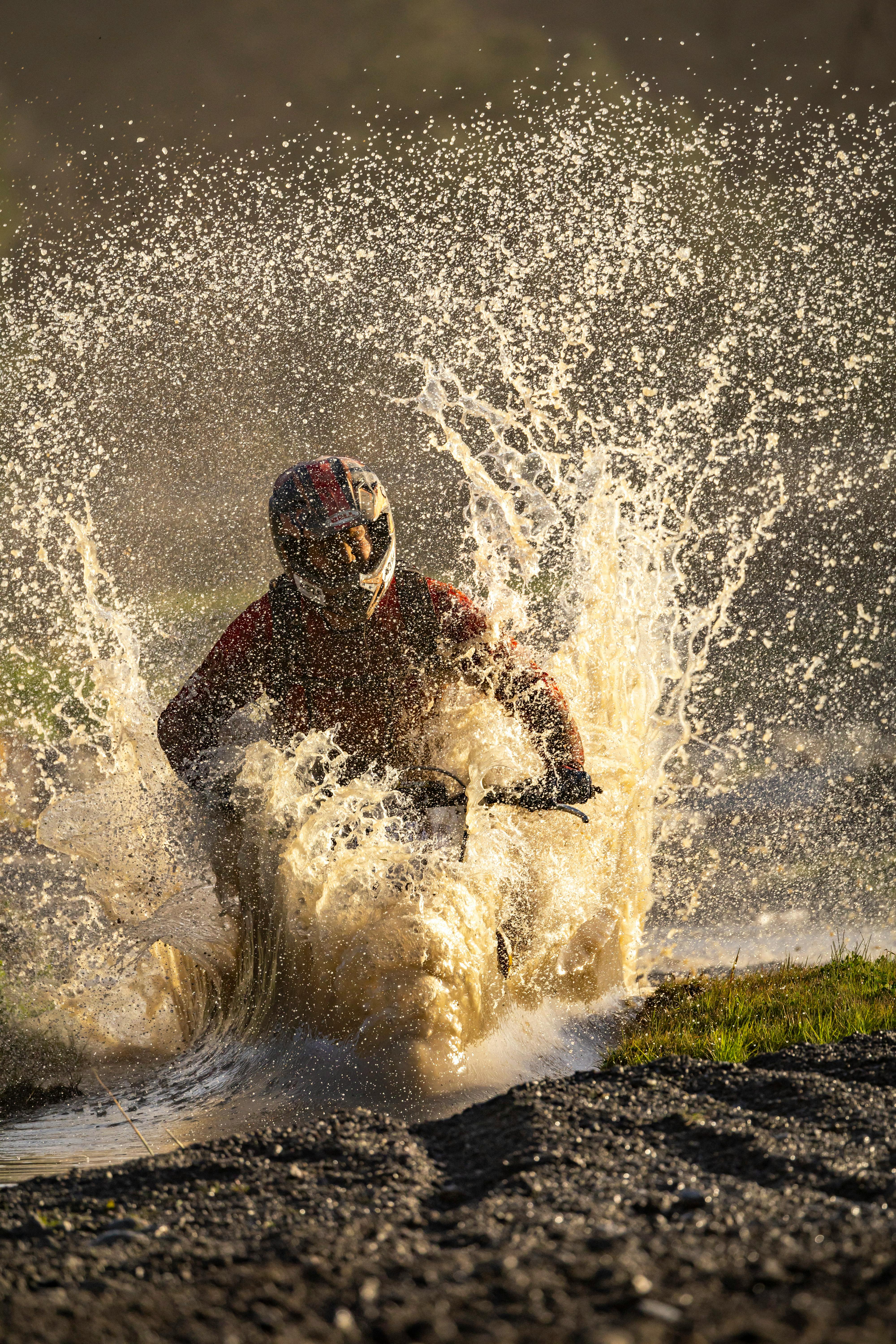 Dirt Biker Riding Through Muddy Splash Outdoors · Free Stock Photo