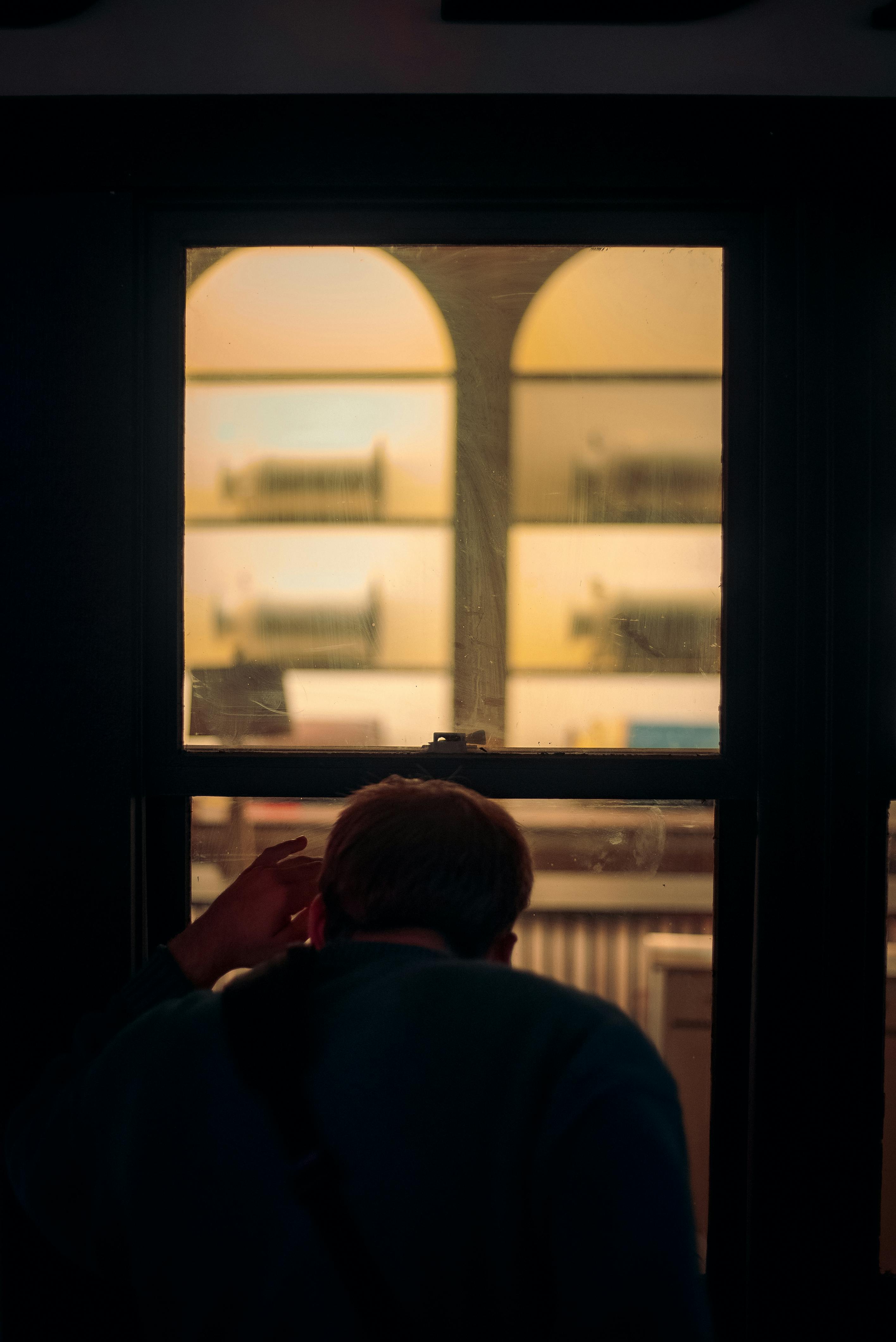 Silhouette of Person Peering Through Window at Night · Free Stock Photo