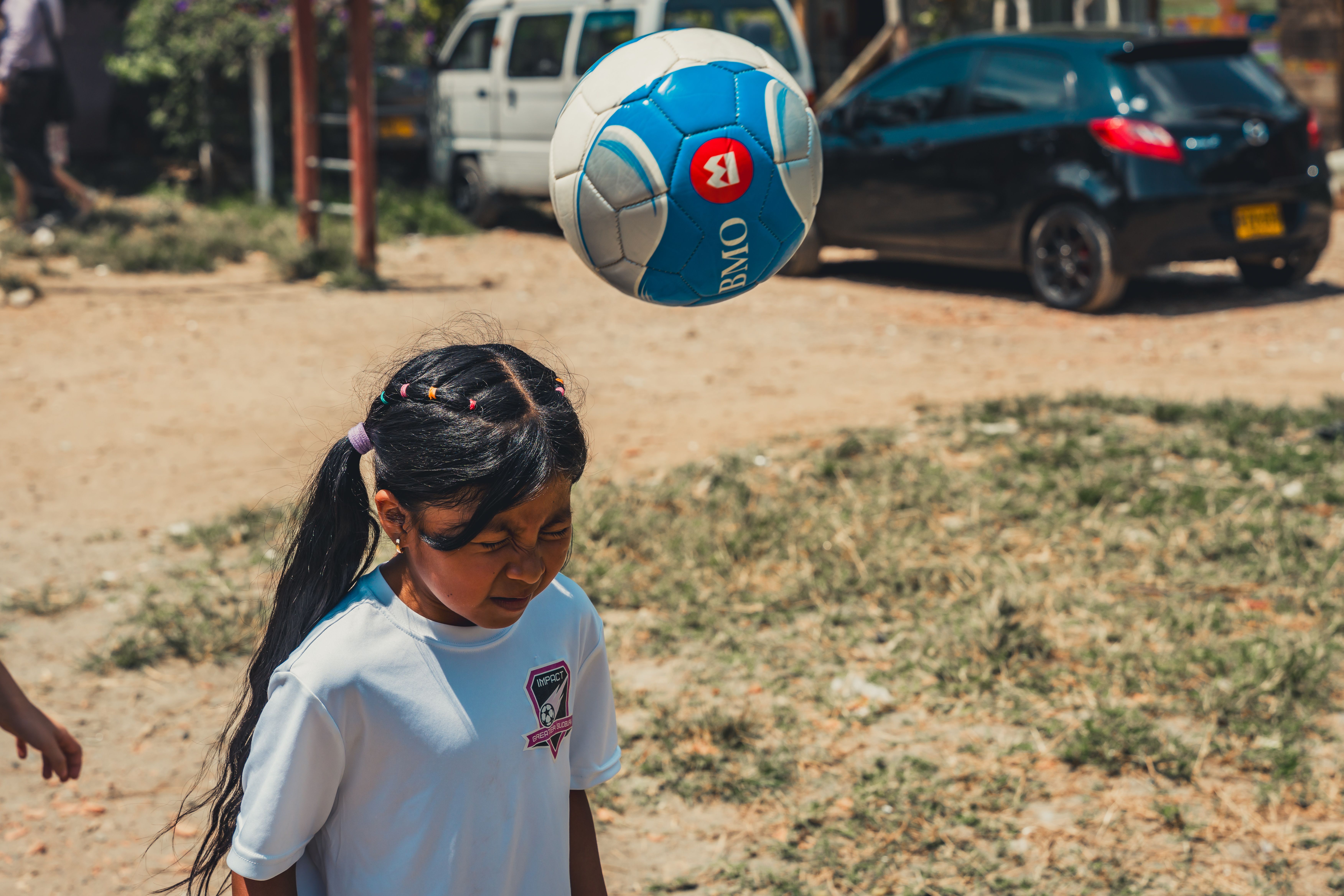 Young girl heading a soccer ball outdoors · Free Stock Photo