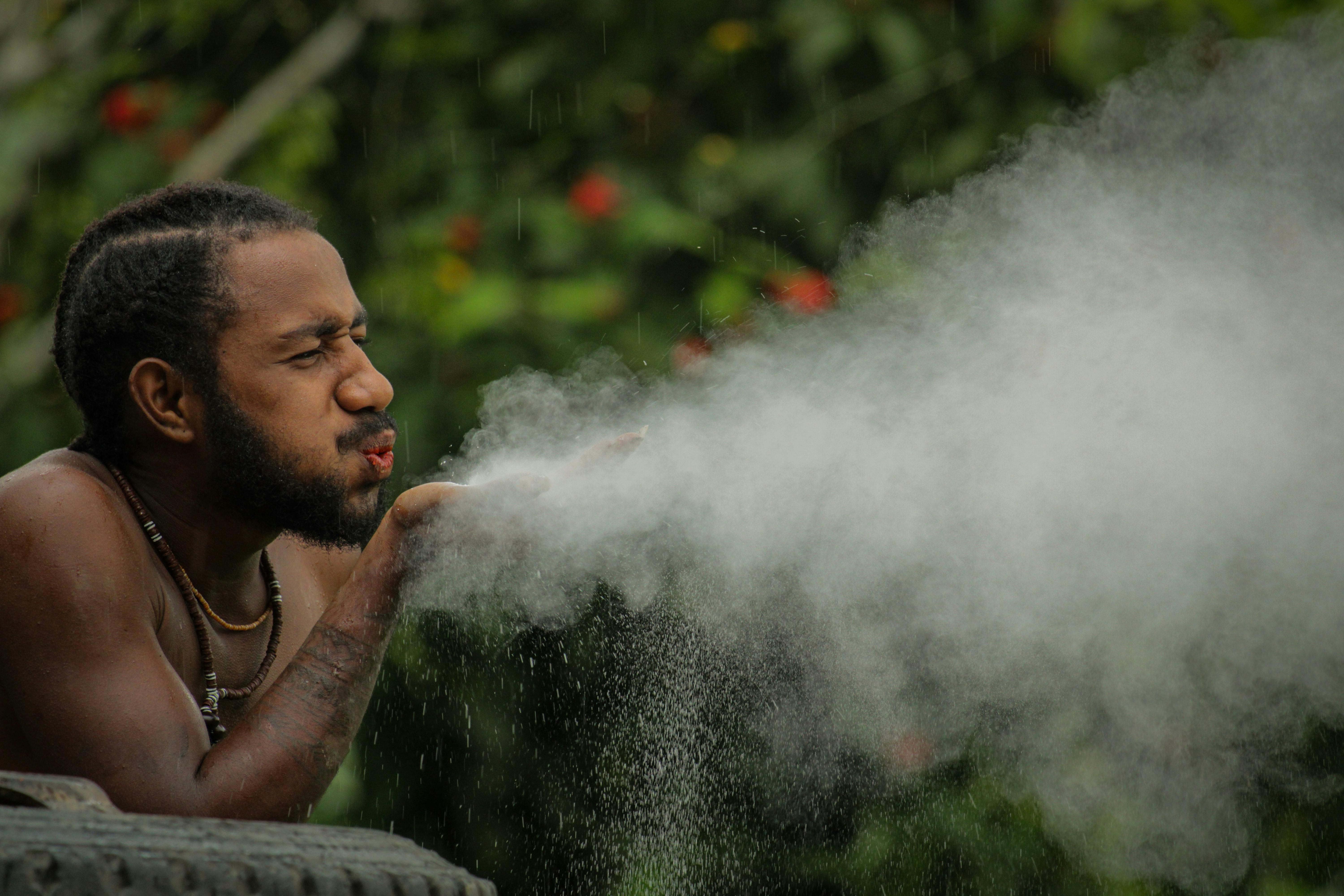 Man Blowing Powder Outdoors in Natural Setting · Free Stock Photo