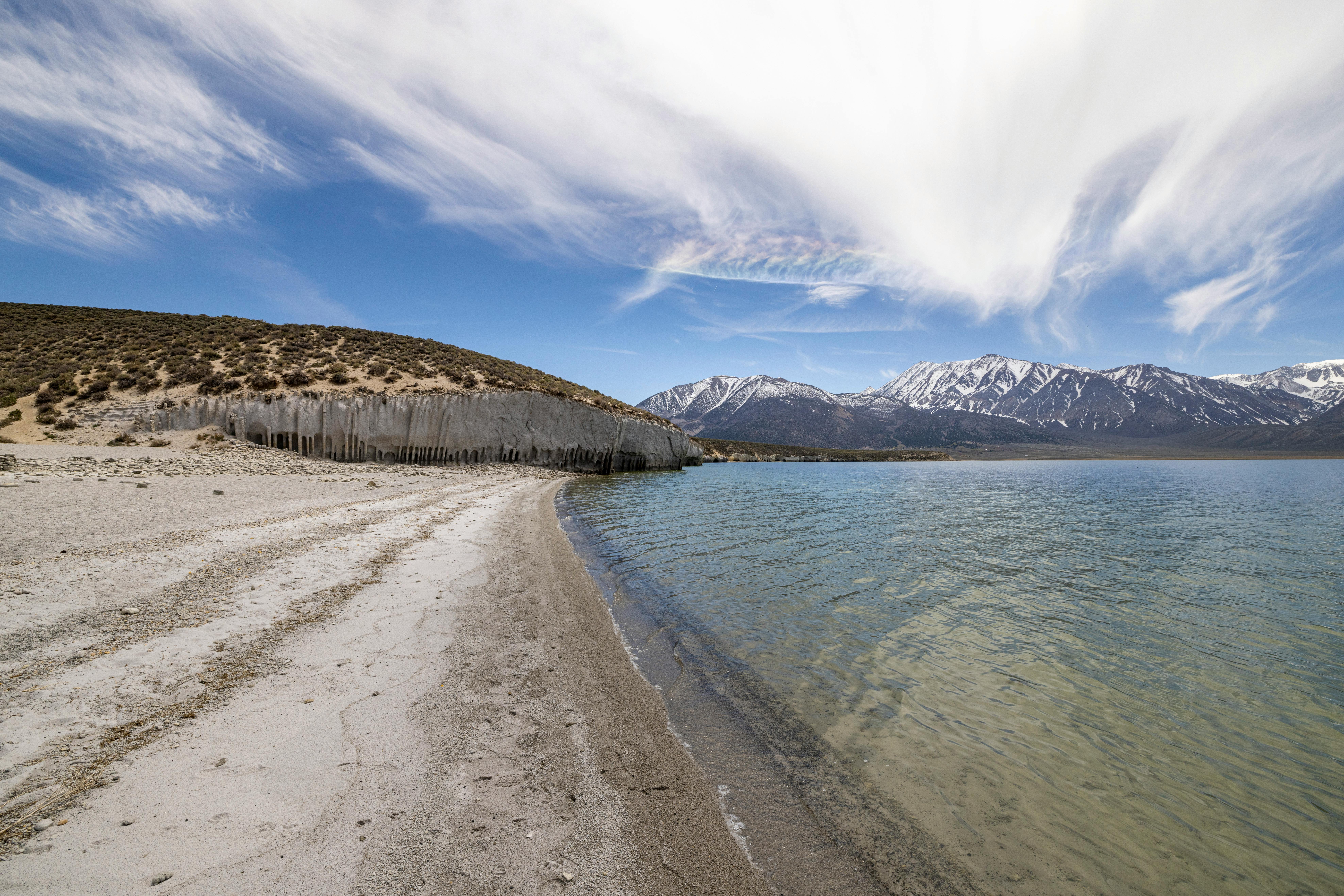 Serene Beachfront with Snow-Capped Mountains · Free Stock Photo