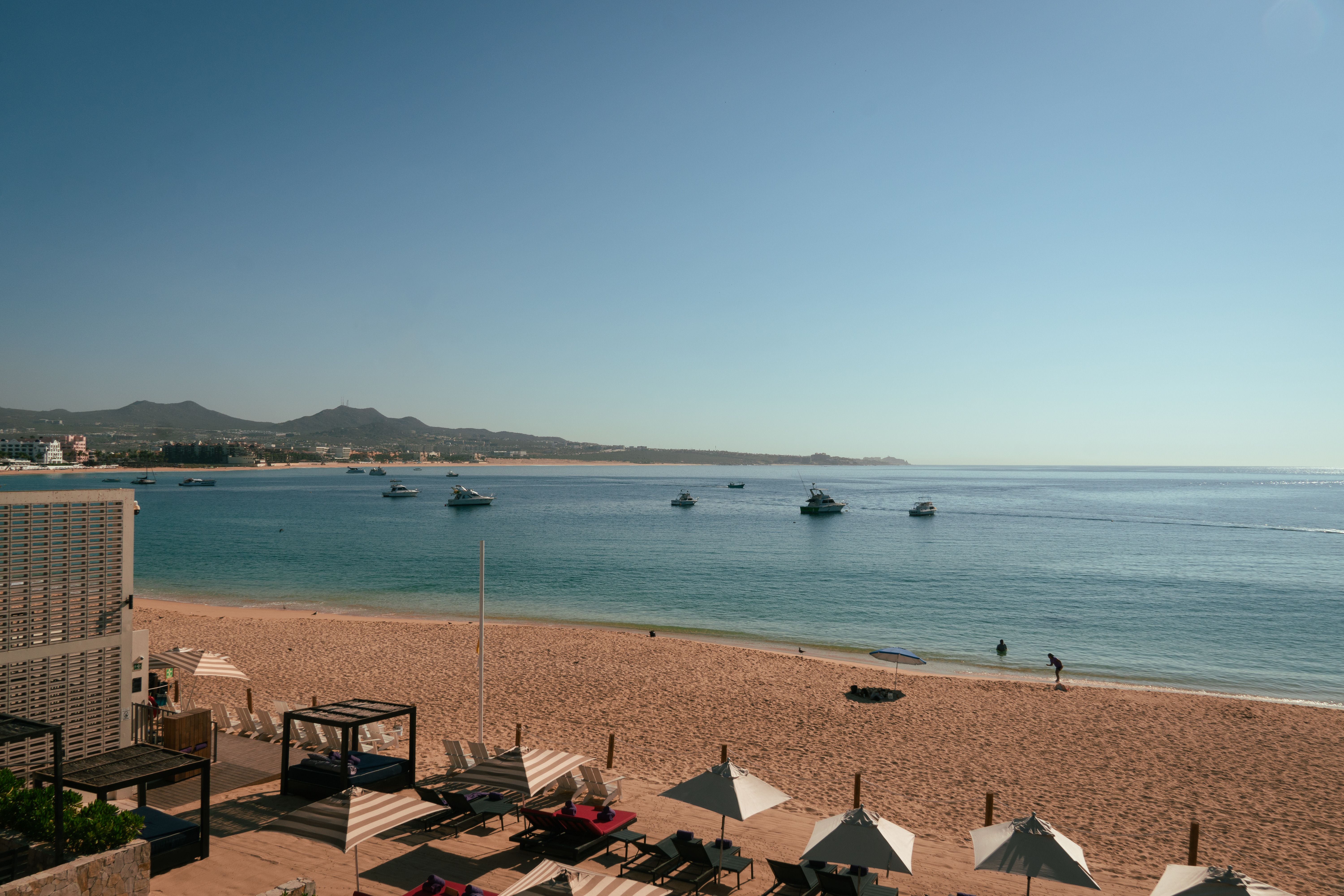 Tranquil Beachfront View with Boats and Mountains · Free Stock Photo