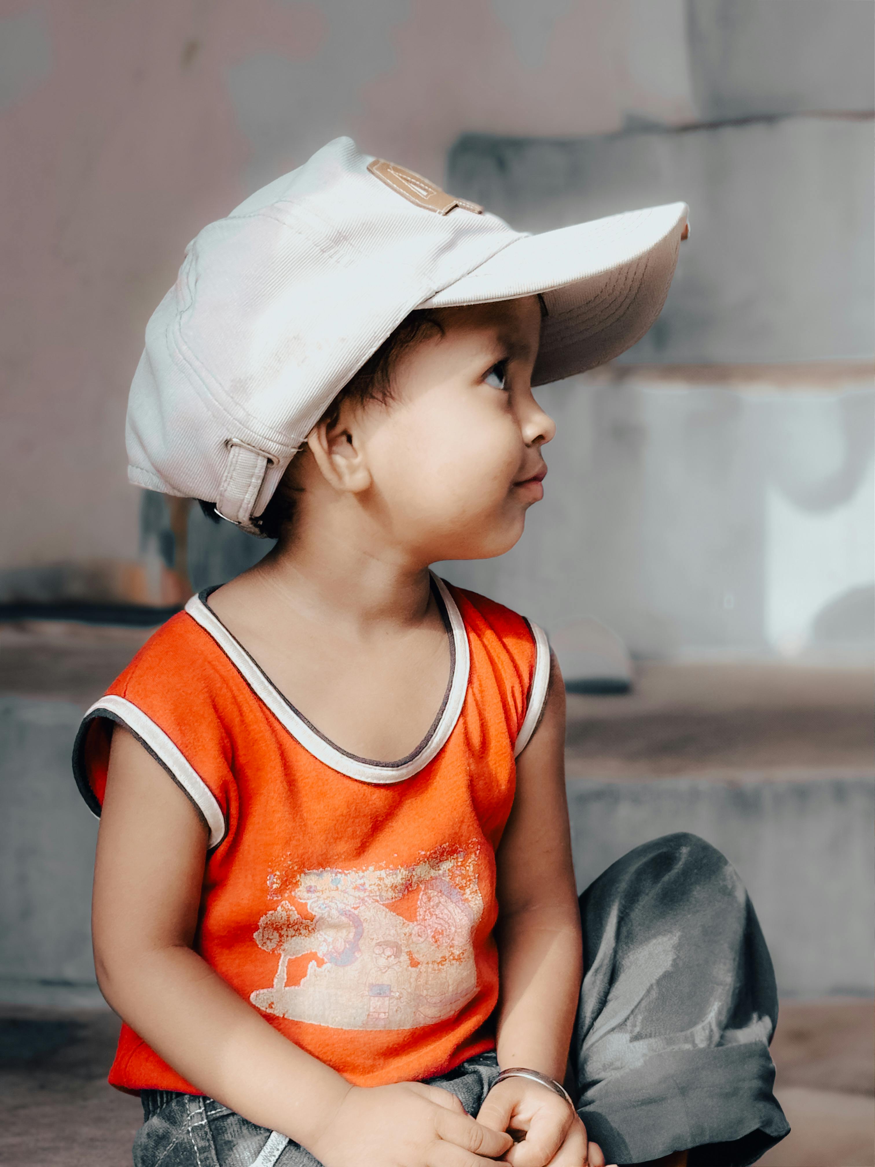 Cute Child Wearing Cap Sitting Indoors · Free Stock Photo
