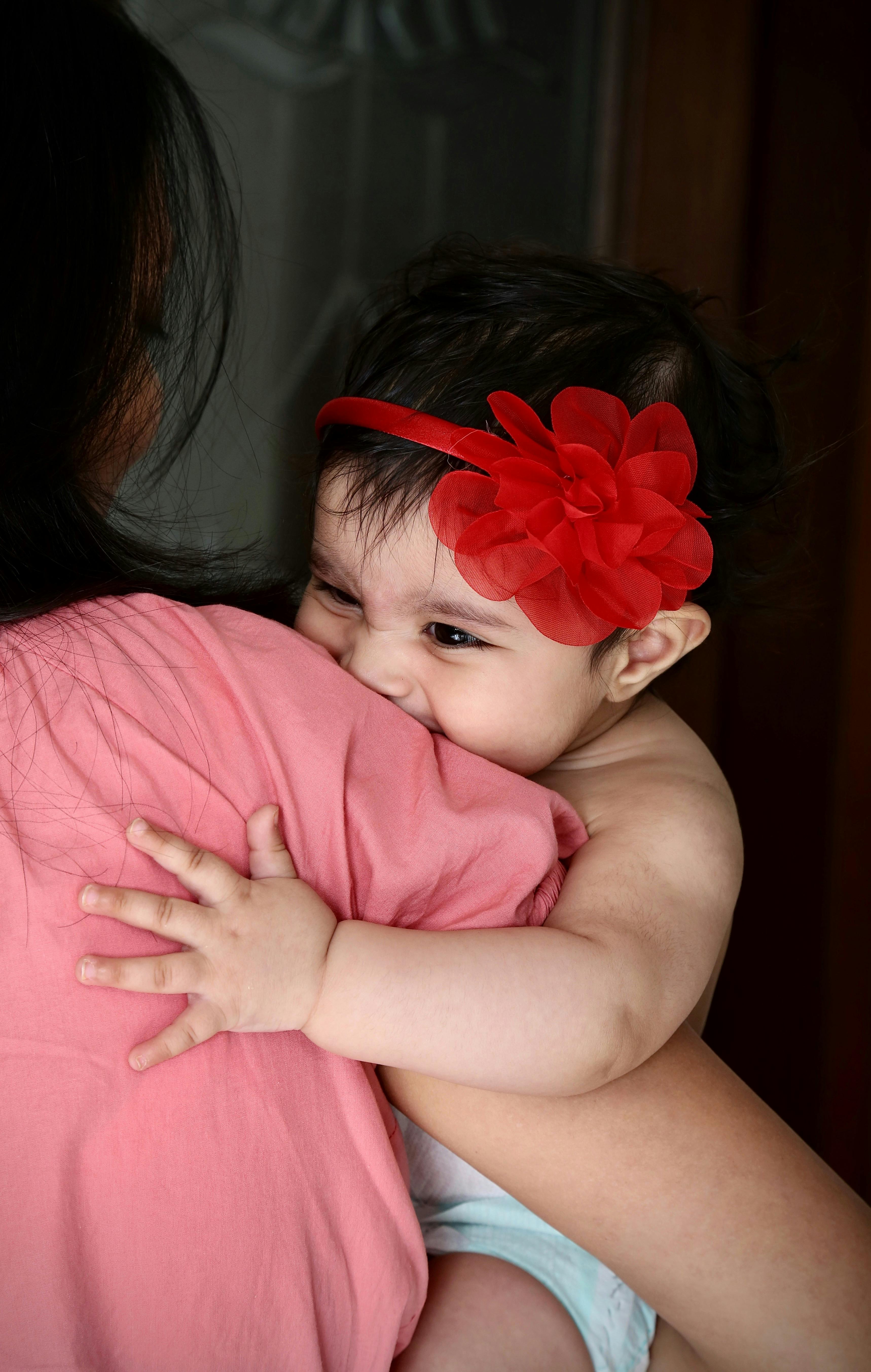 Cute Baby with Red Headband Biting Mother's Shoulder · Free Stock Photo
