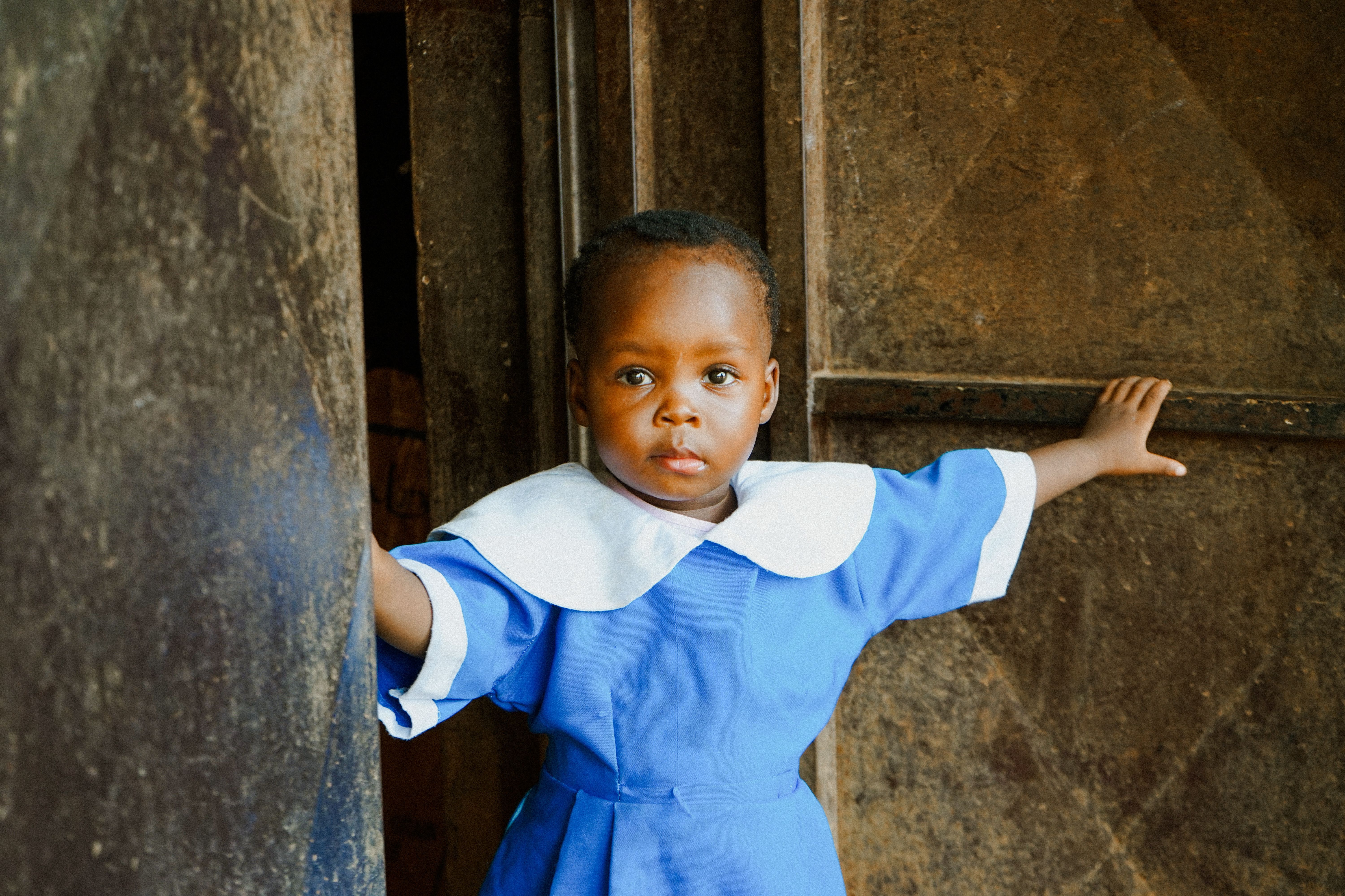 Adorable Child in Blue School Uniform by Doorway · Free Stock Photo