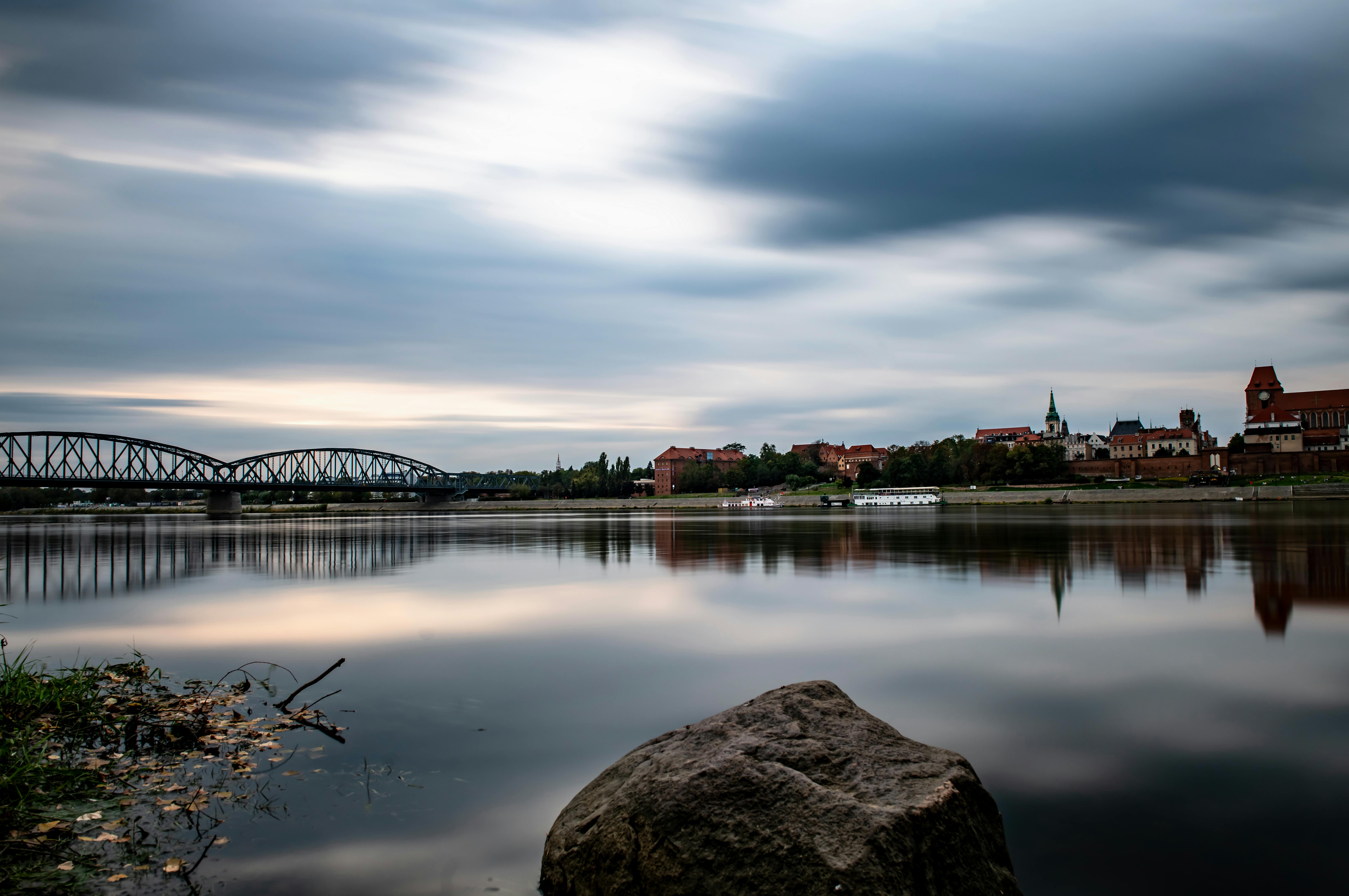 Serene Riverside View with Historic Bridge and Town · Free Stock Photo