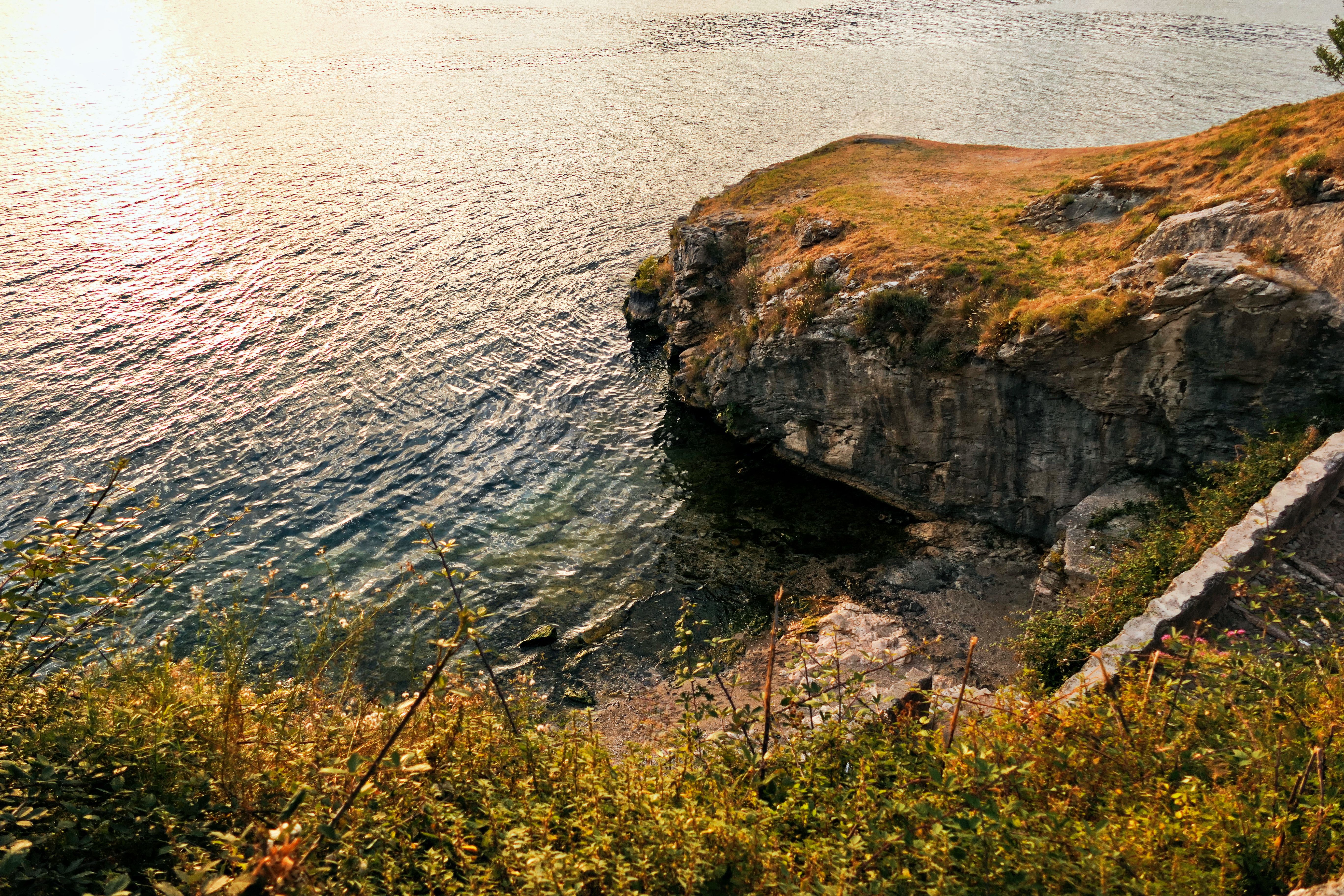 Scenic Coastal Cliff at Sunset with Calm Waters · Free Stock Photo