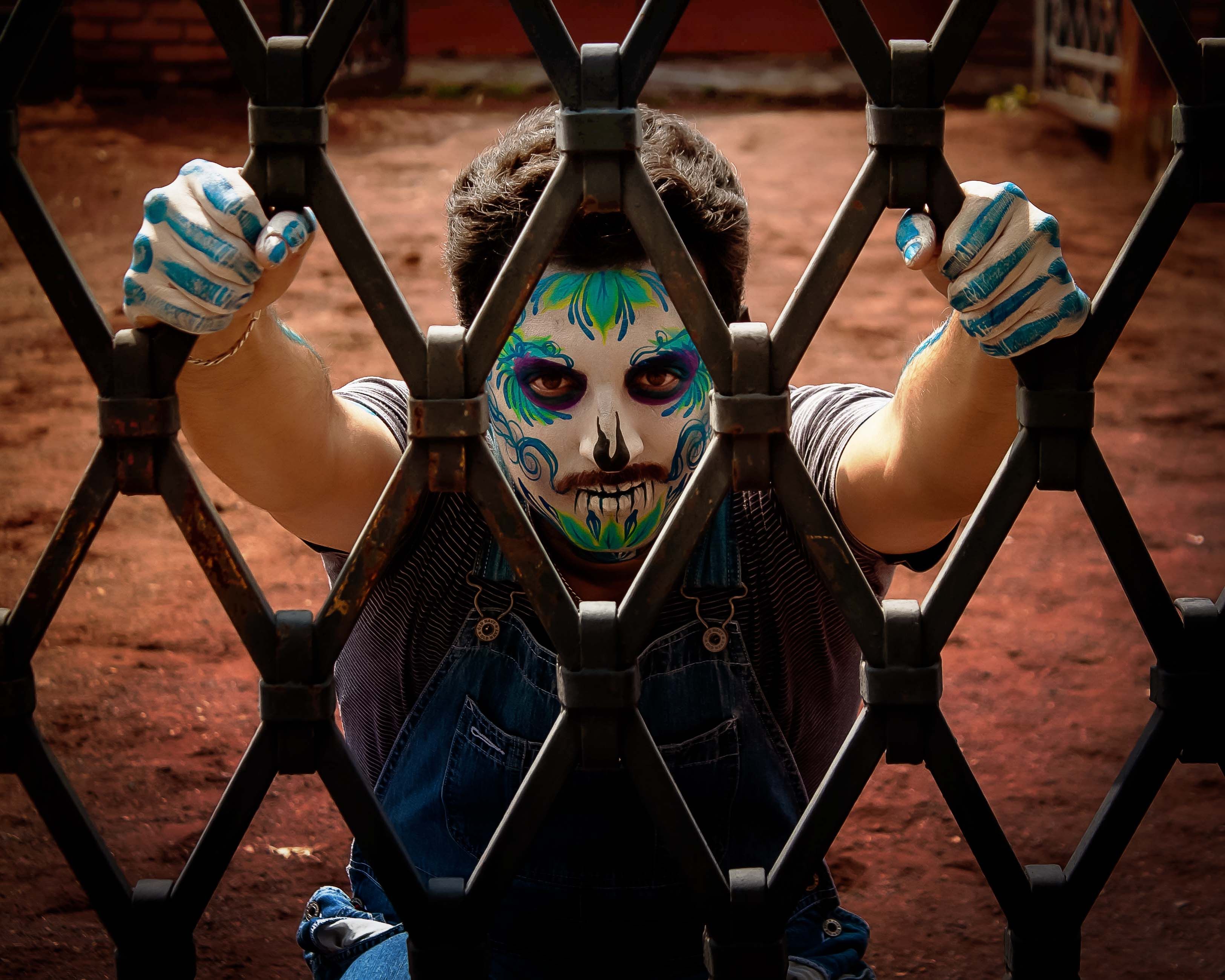 Man with Painted Face Behind Metal Gate · Free Stock Photo