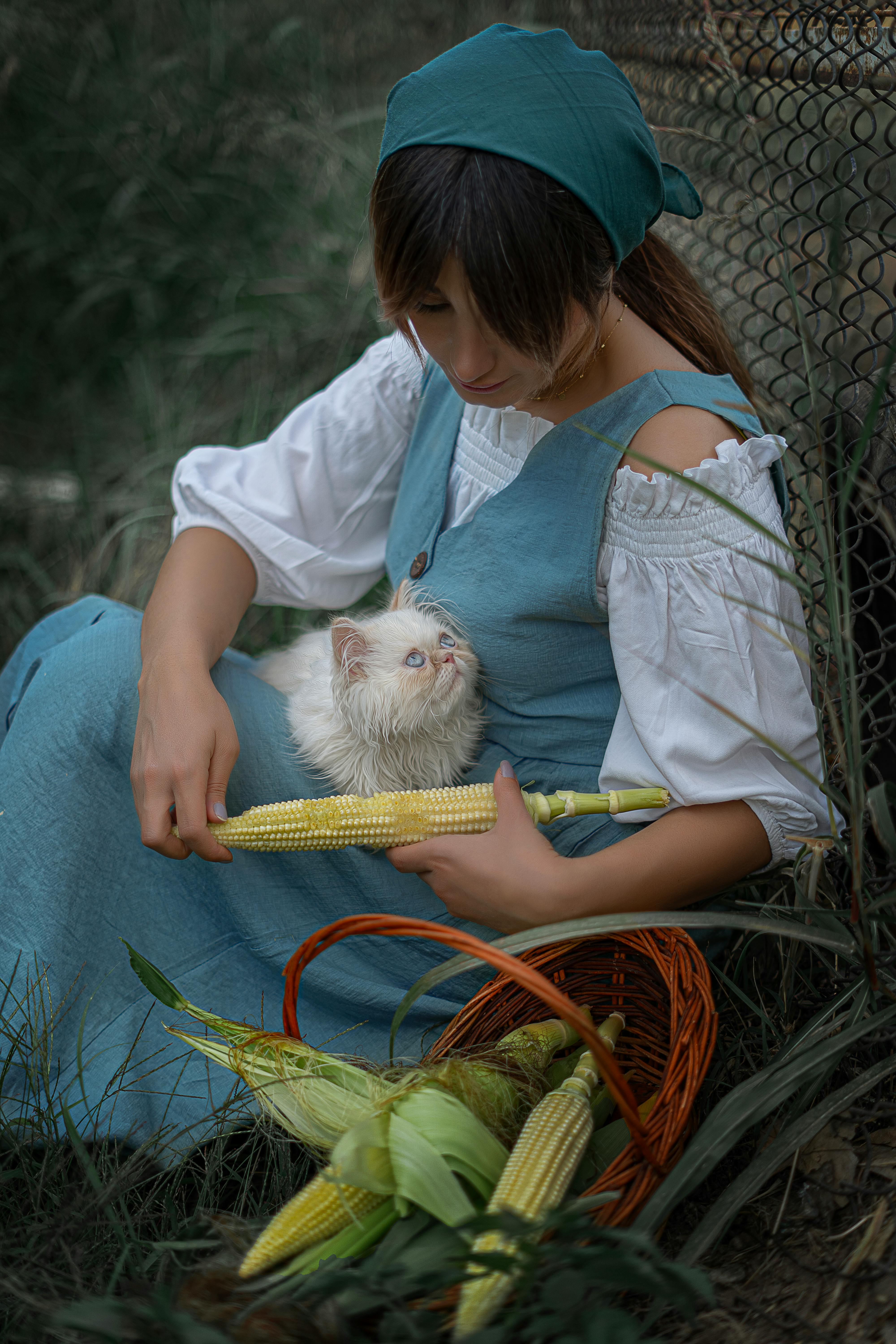 Young Woman with Cat in Rural Setting Holding Corn · Free Stock Photo
