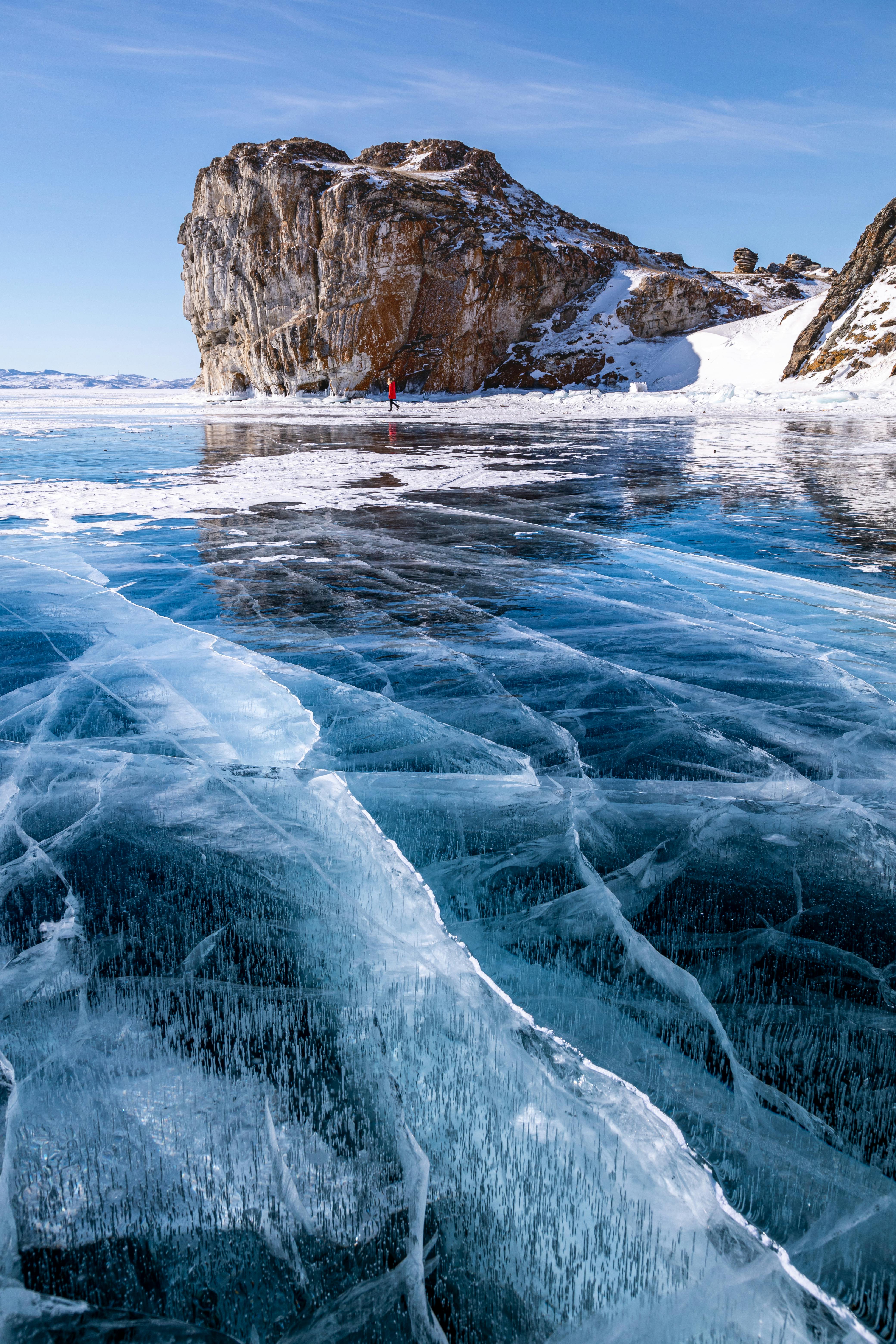 Frozen Lake with Cracked Ice and Rocky Cliff · Free Stock Photo