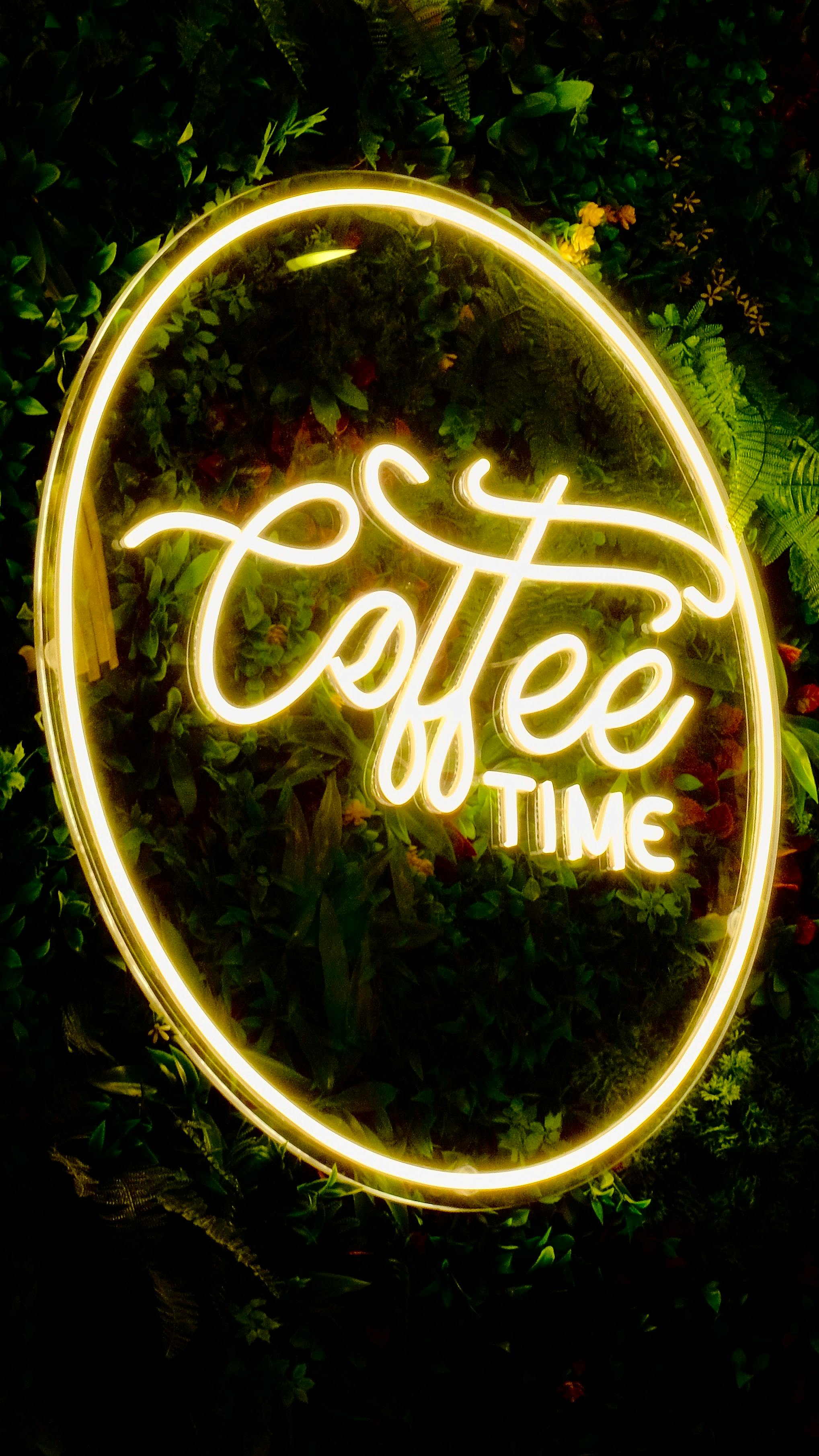 Illuminated Coffee Time Neon Sign on Greenery · Free Stock Photo